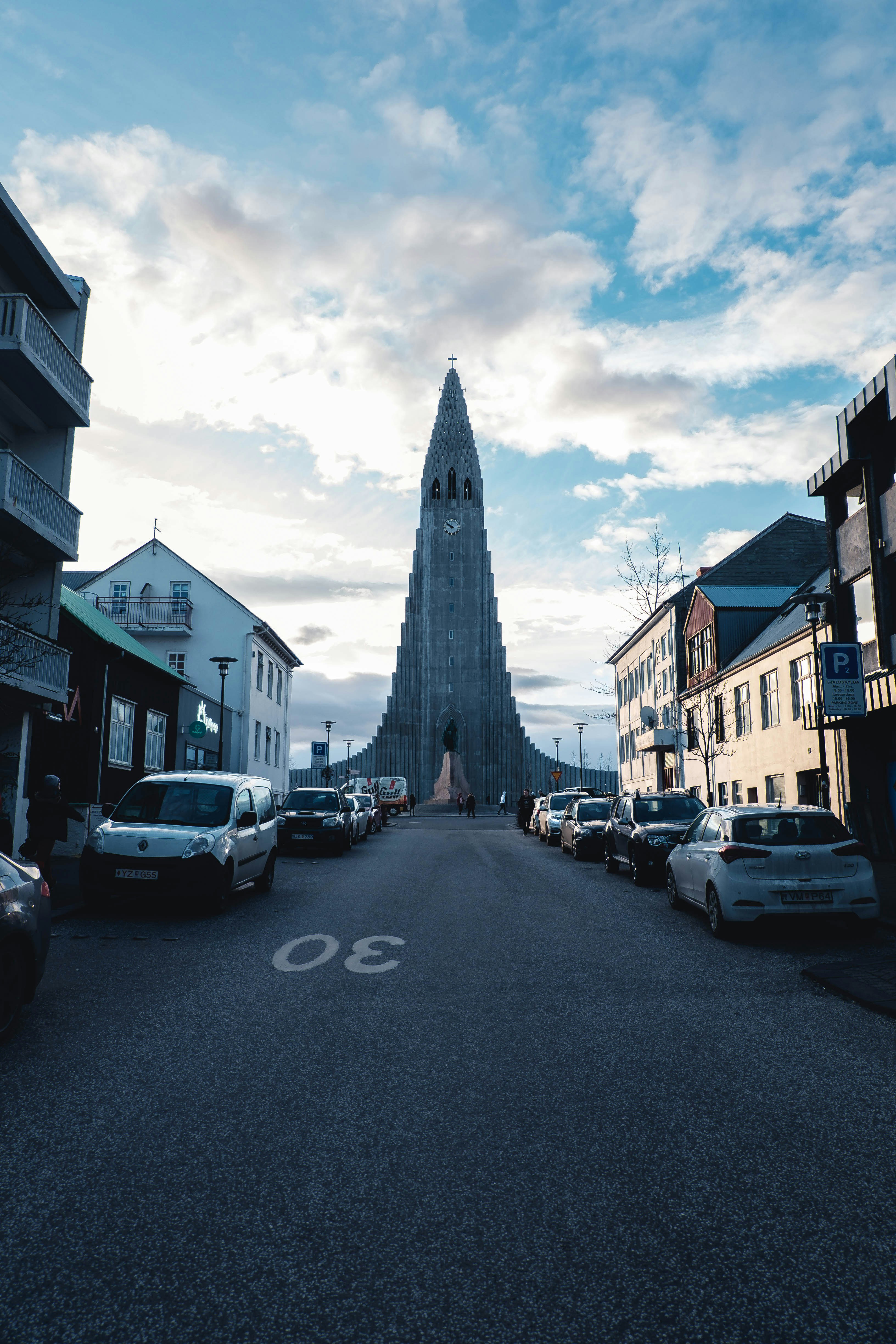 A street lined with parked cars next to tall buildings photo – Free ...