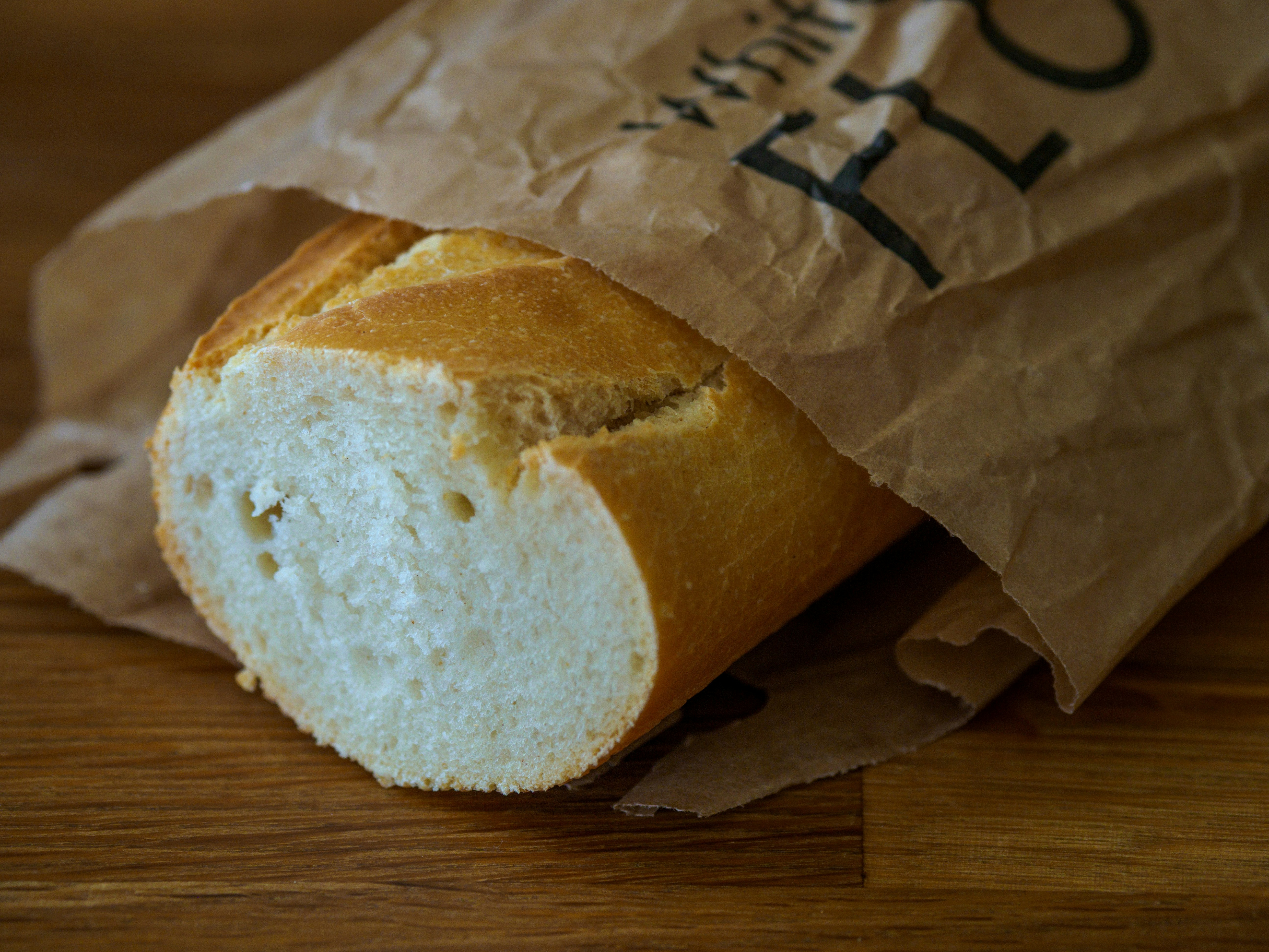 Freshly baked artisan bread partially revealed from a rustic paper bag, showcasing its golden crust and soft interior.