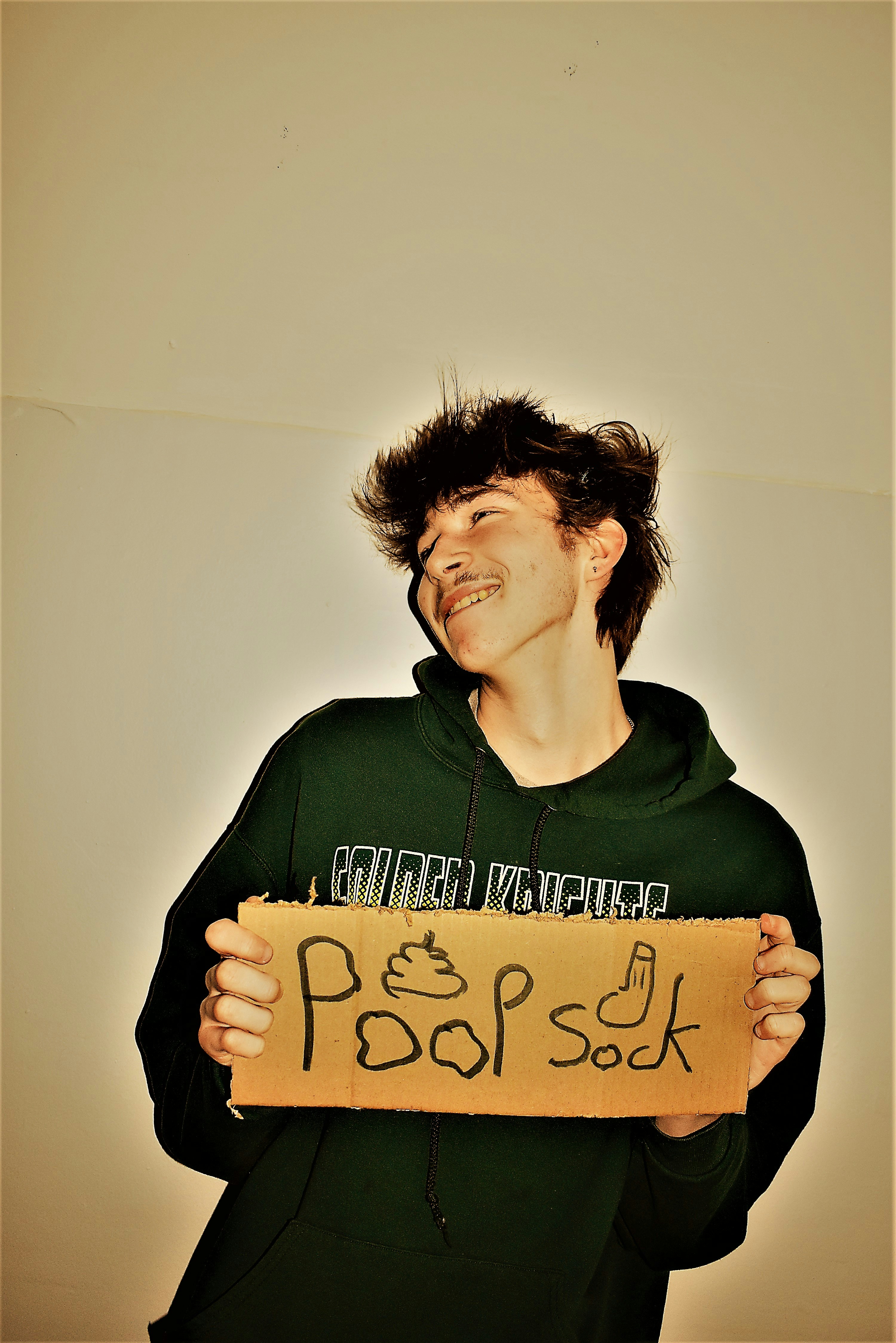 Young person holding a cardboard sign with playful text and illustrations, showcasing a lighthearted moment.