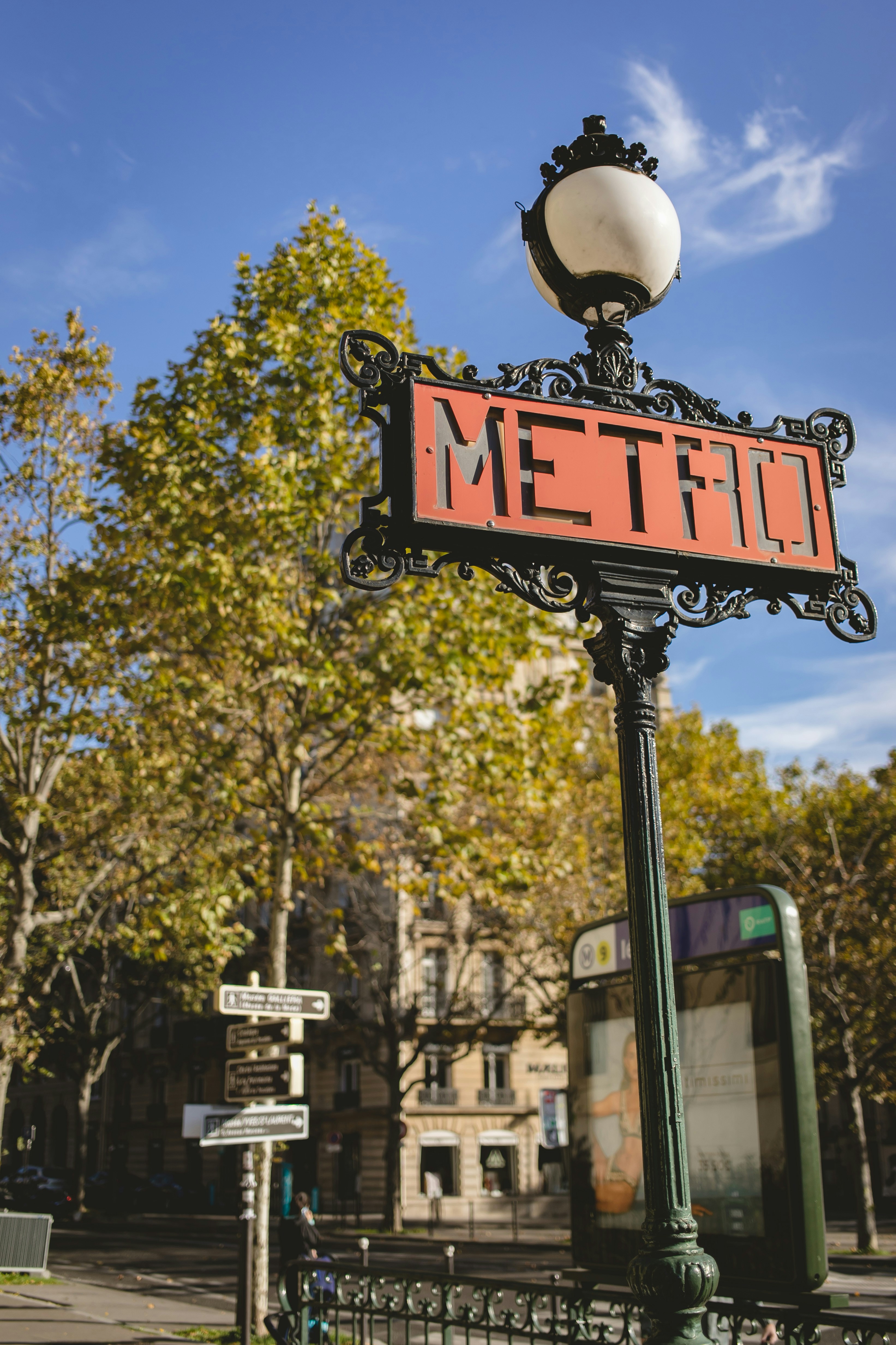 Ornate Metro Sign Amid Autumn Light on a Sunlit City Street