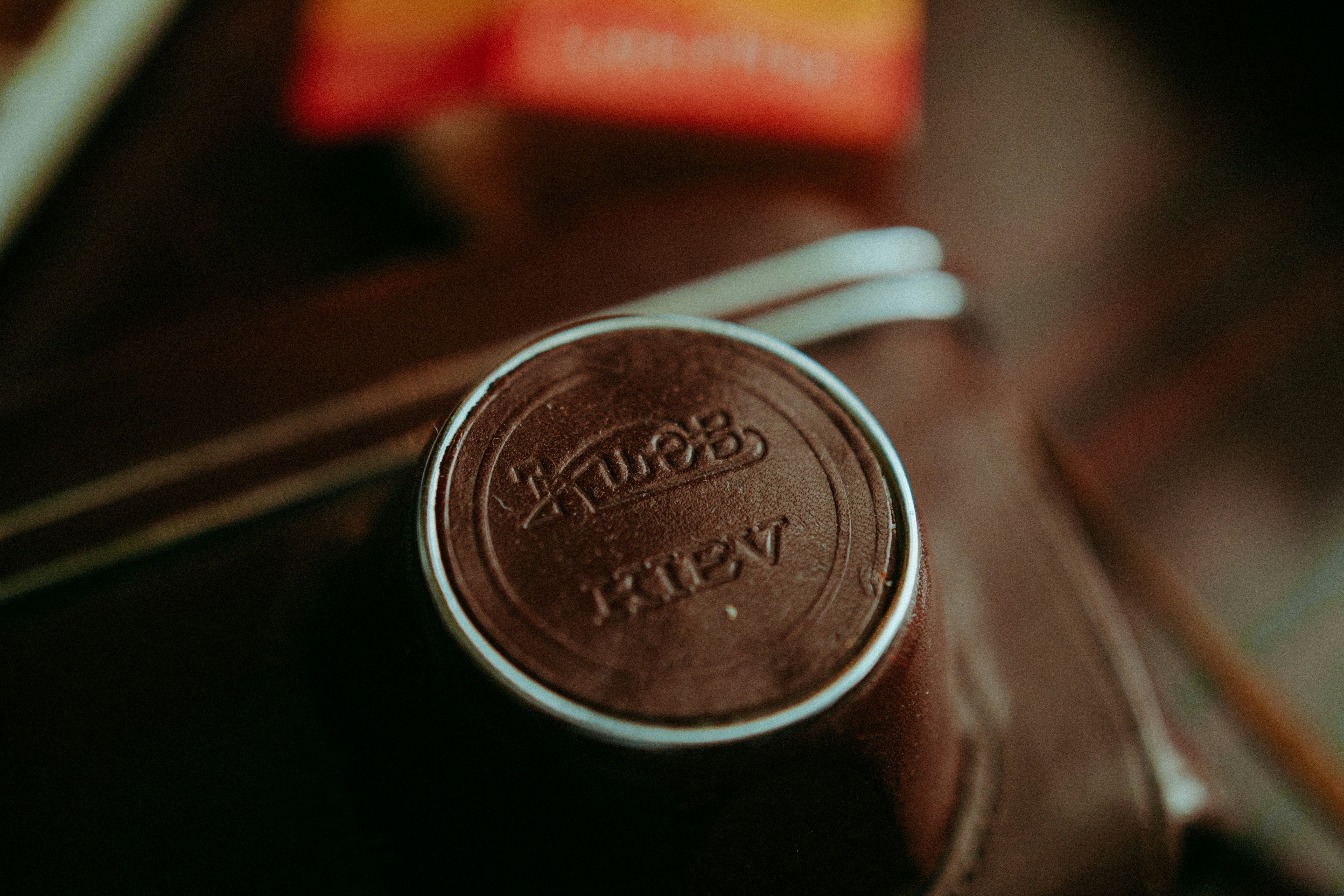 Close-up of a vintage Argent pocket lens cap resting on a leather bag