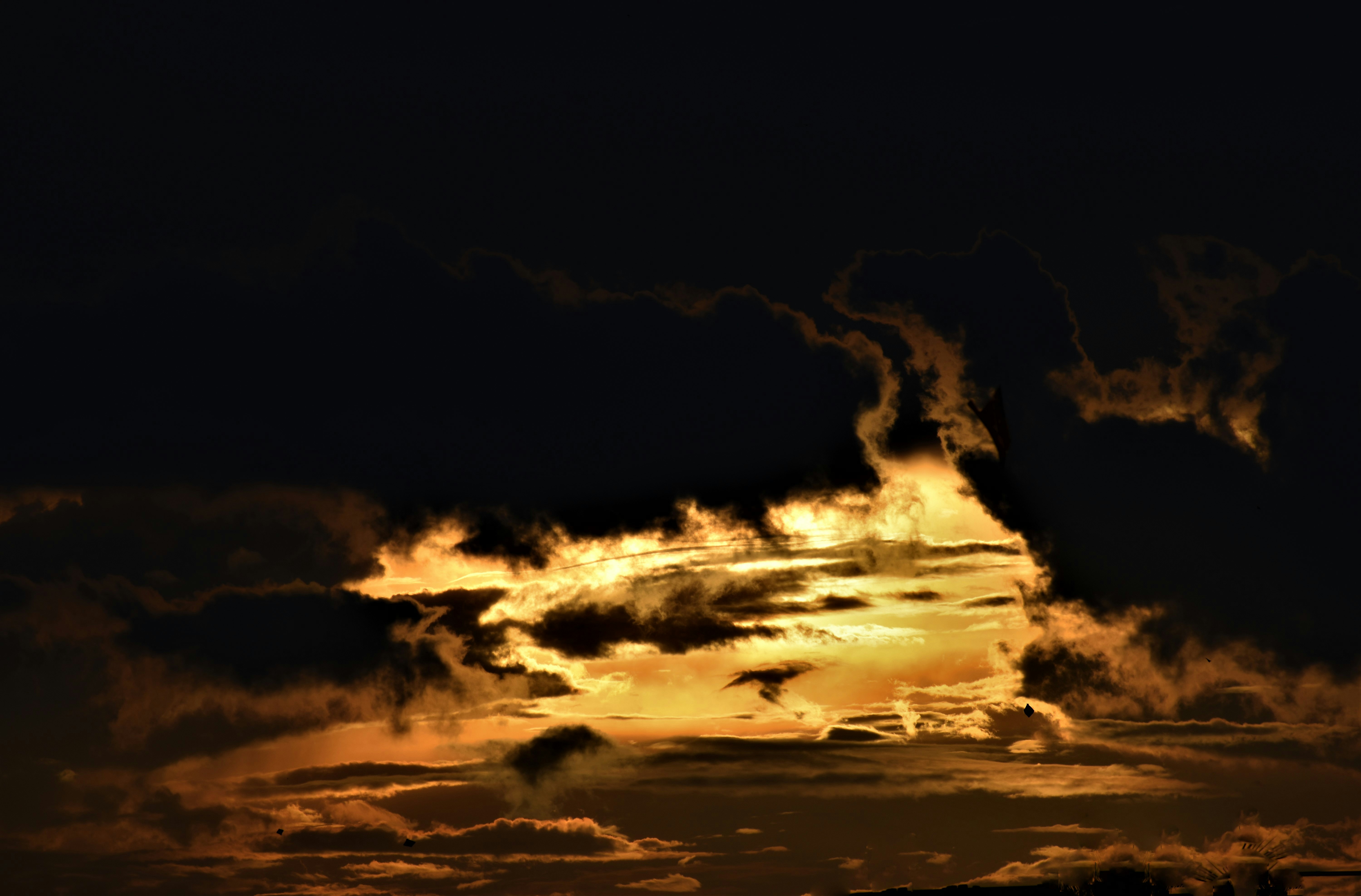 Dramatic clouds illuminated by a golden hue, creating a striking contrast against the darkening sky.