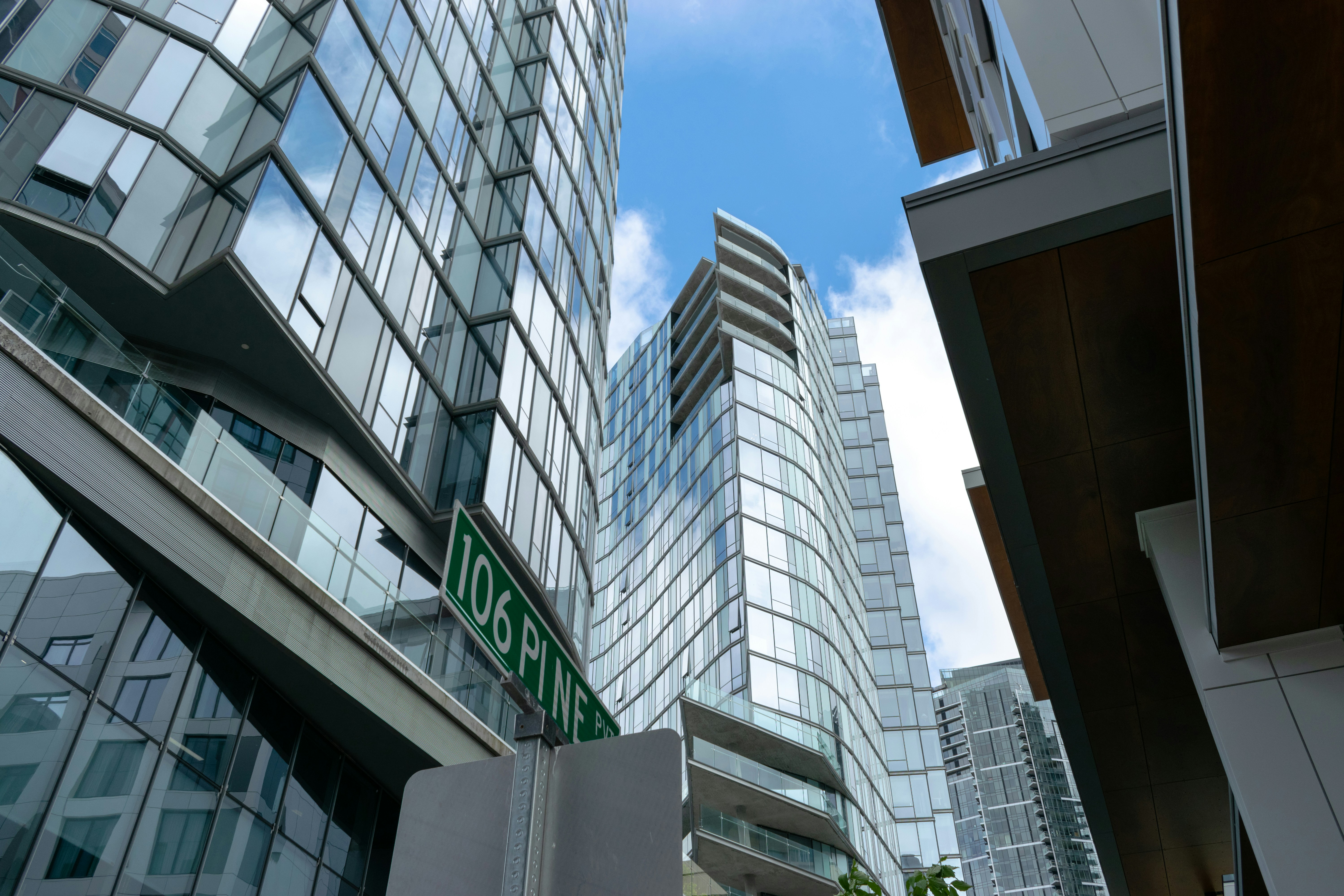 Glass skyscrapers reflecting the sky and each other in a bustling urban environment.