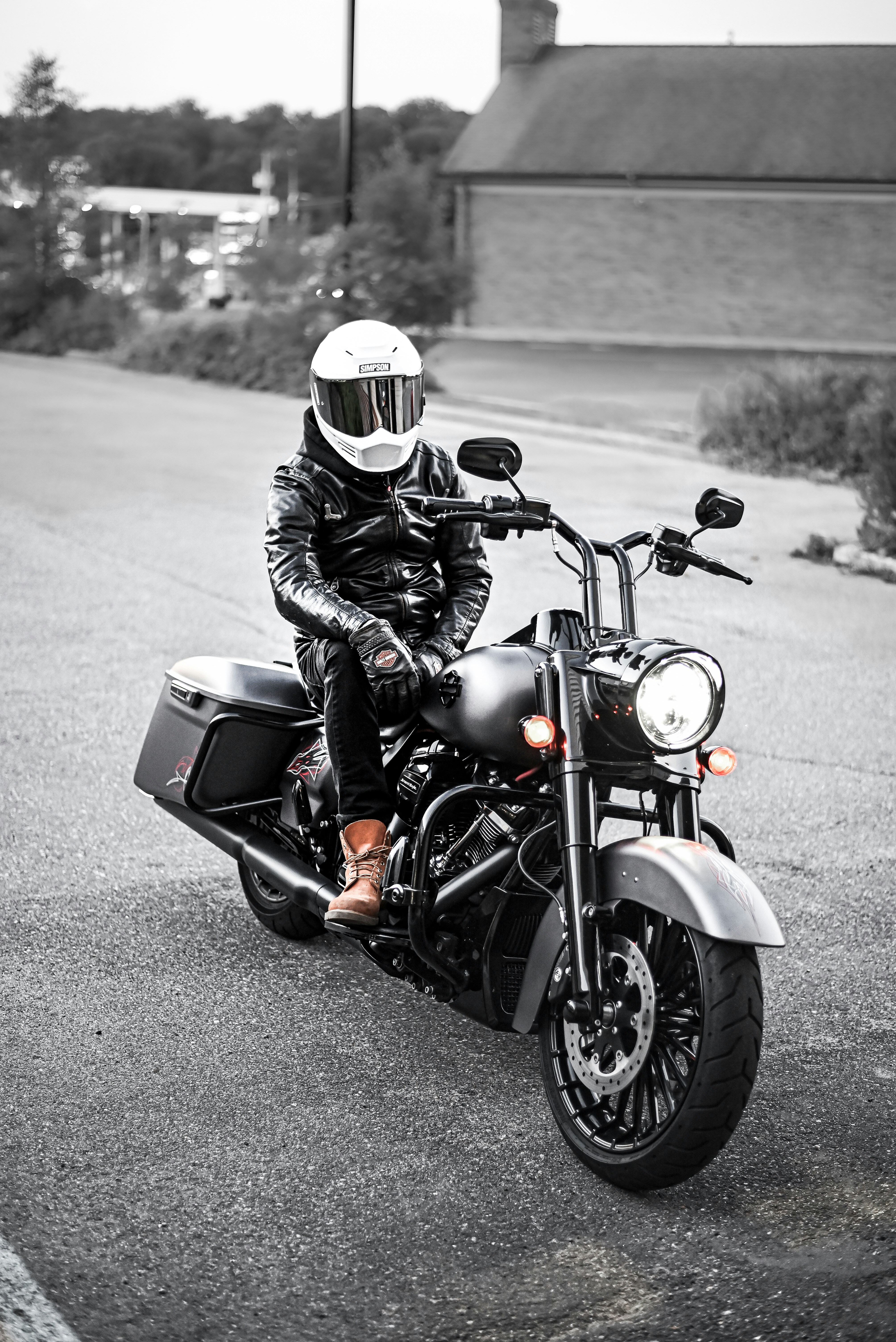 Motorcyclist dressed in leather gear sits on a sleek black motorcycle, helmet reflecting the surroundings. The scene conveys a sense of adventure and contemplation.