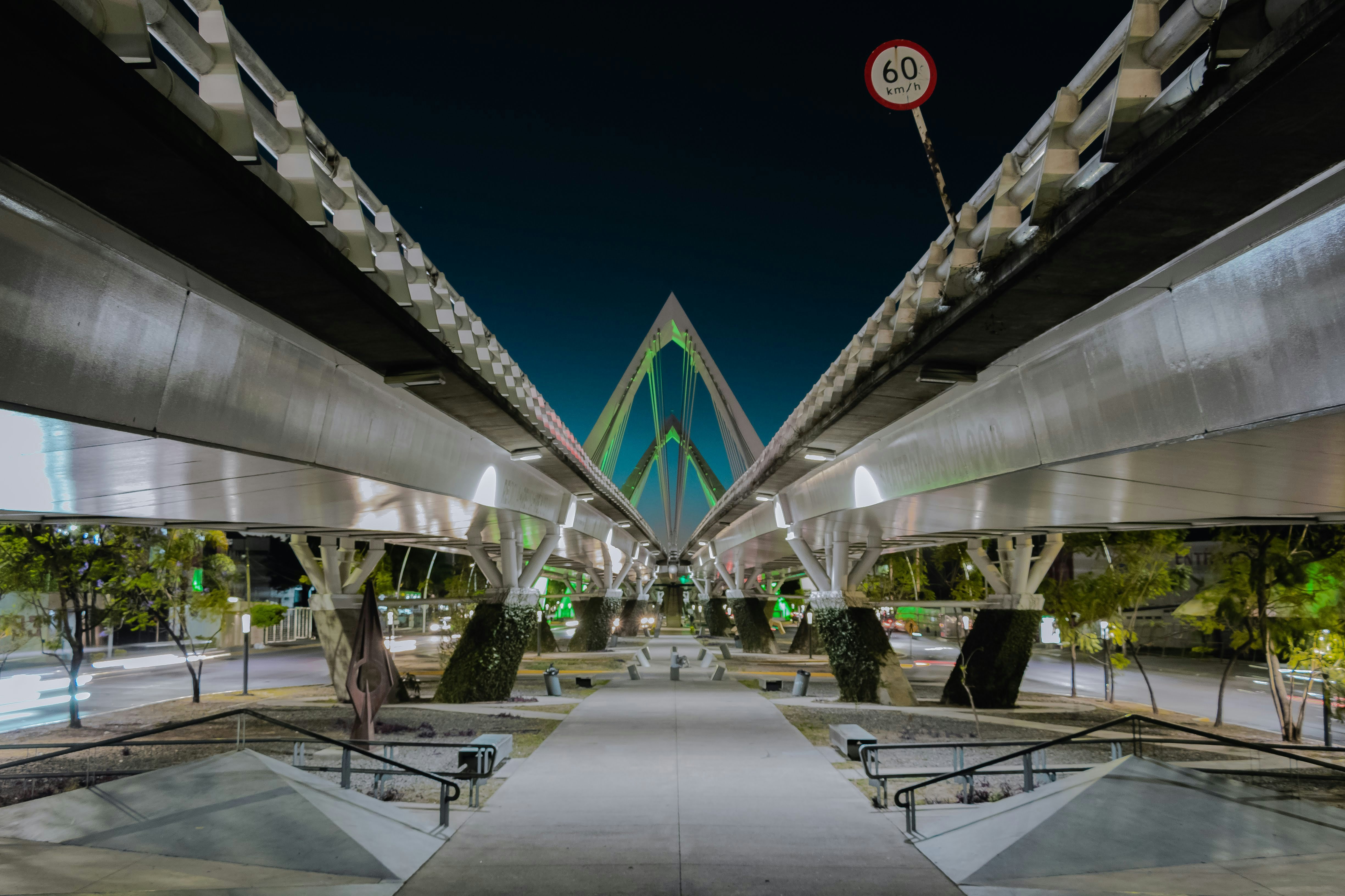 Symmetrical view of a modern bridge with illuminated archways under a night sky.