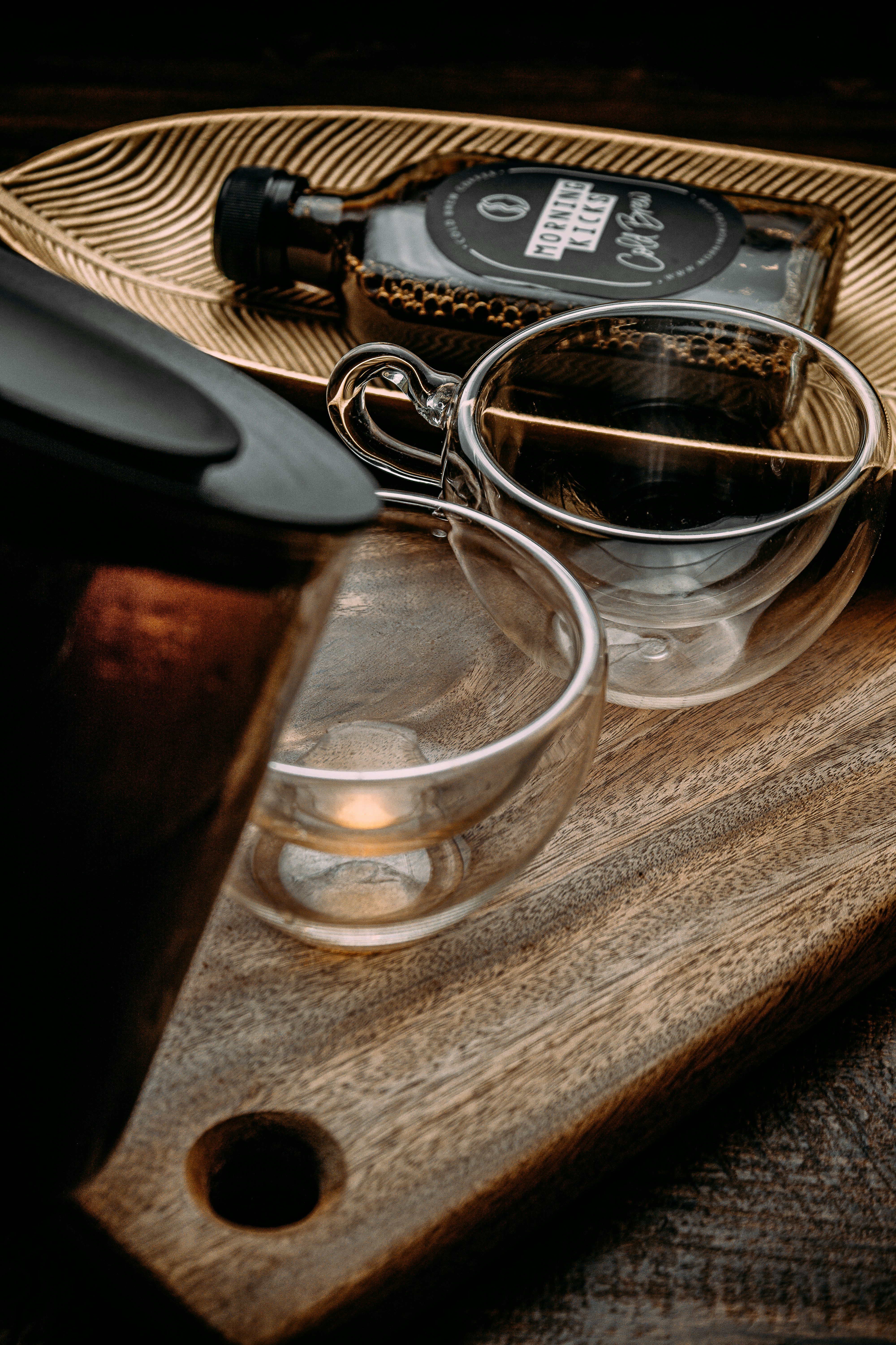 Warm Reflections on a Wooden Tray: Glass Cups and a Dark-Label Bottle