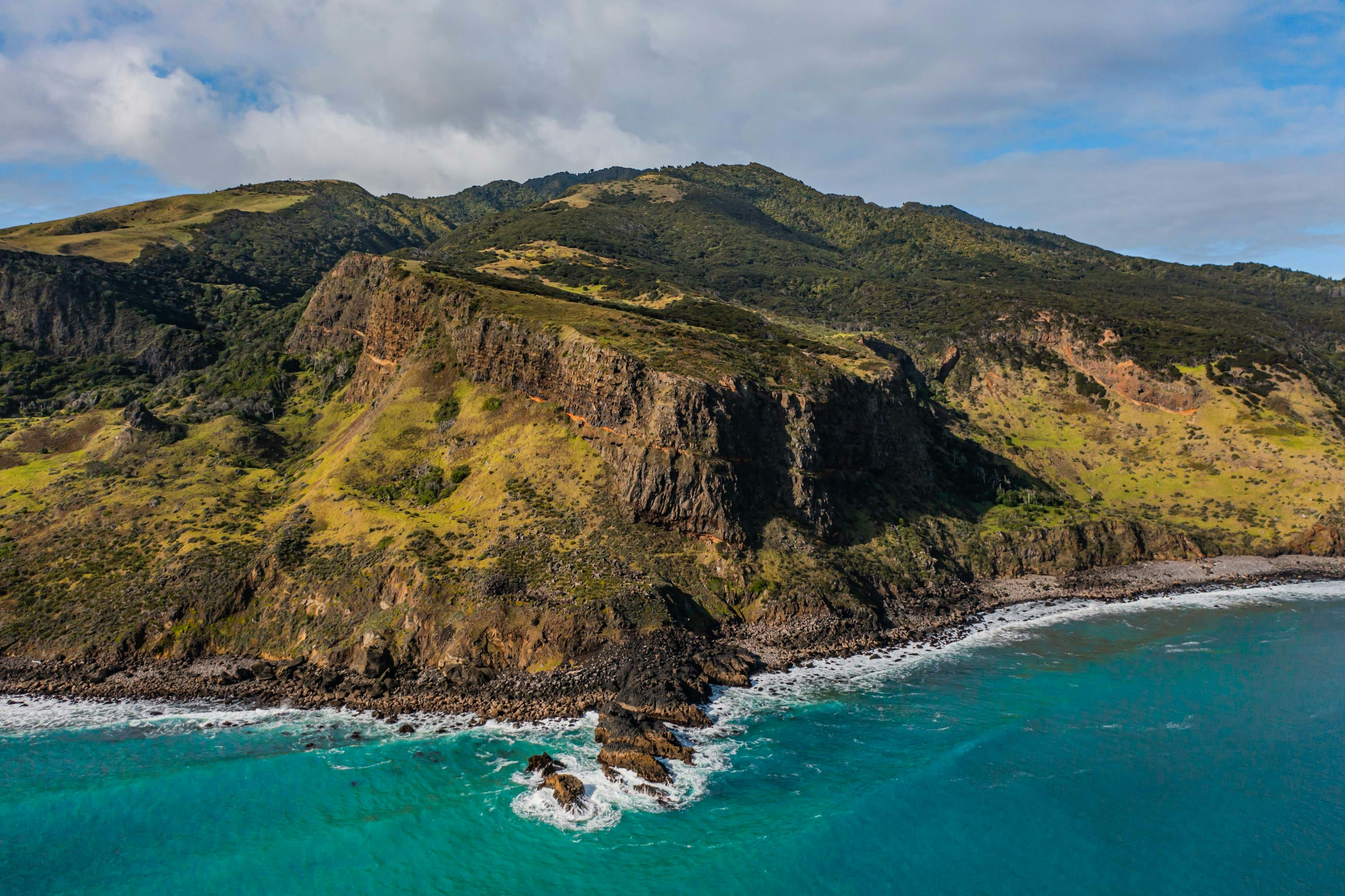 Aerial view of a dramatic coastline where steep cliffs meet the vibrant turquoise waters, showcasing the interplay of land and ocean.