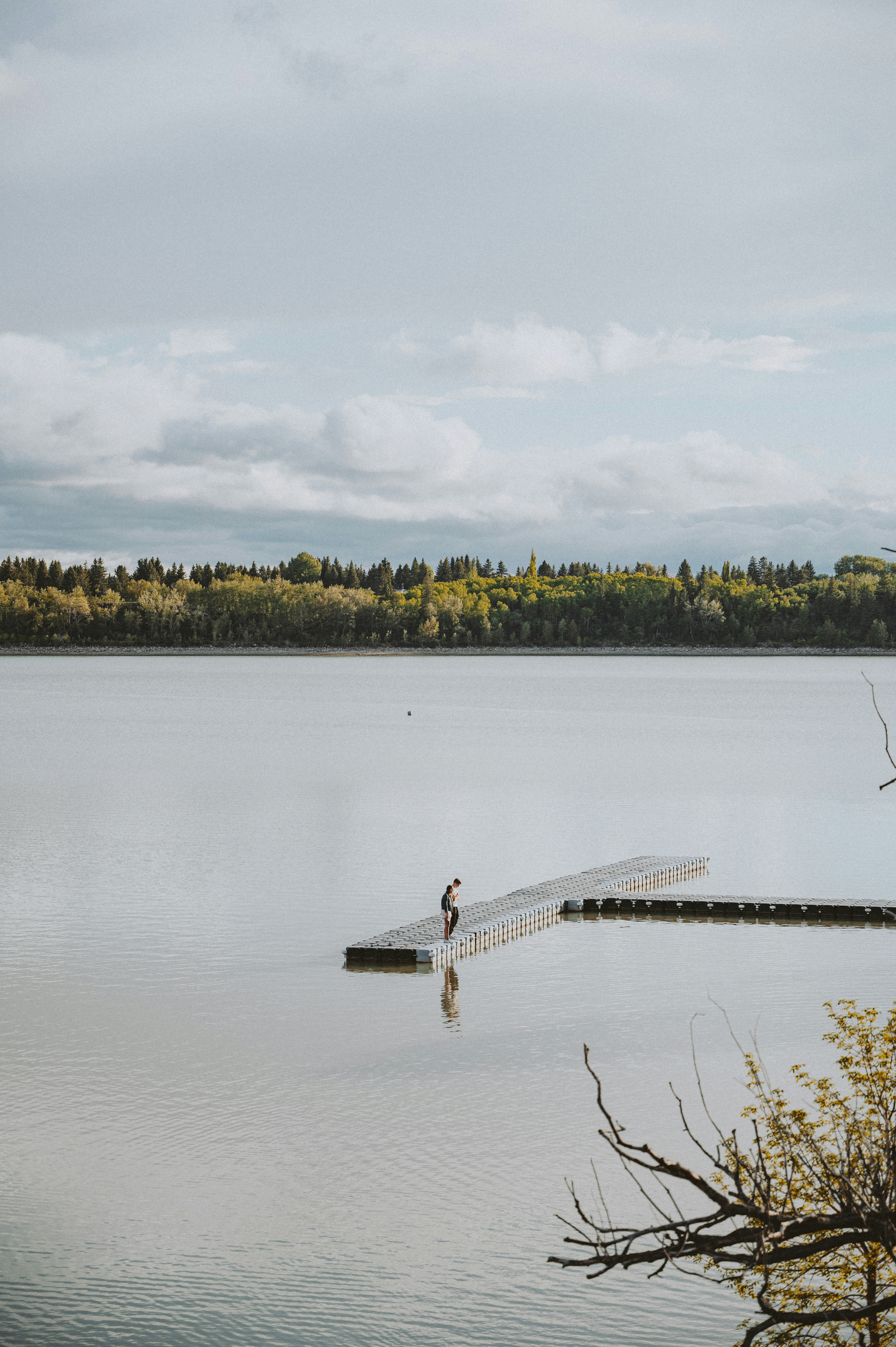 Lone Figure at the End of a Narrow Dock Over a Mirror-Like Lake