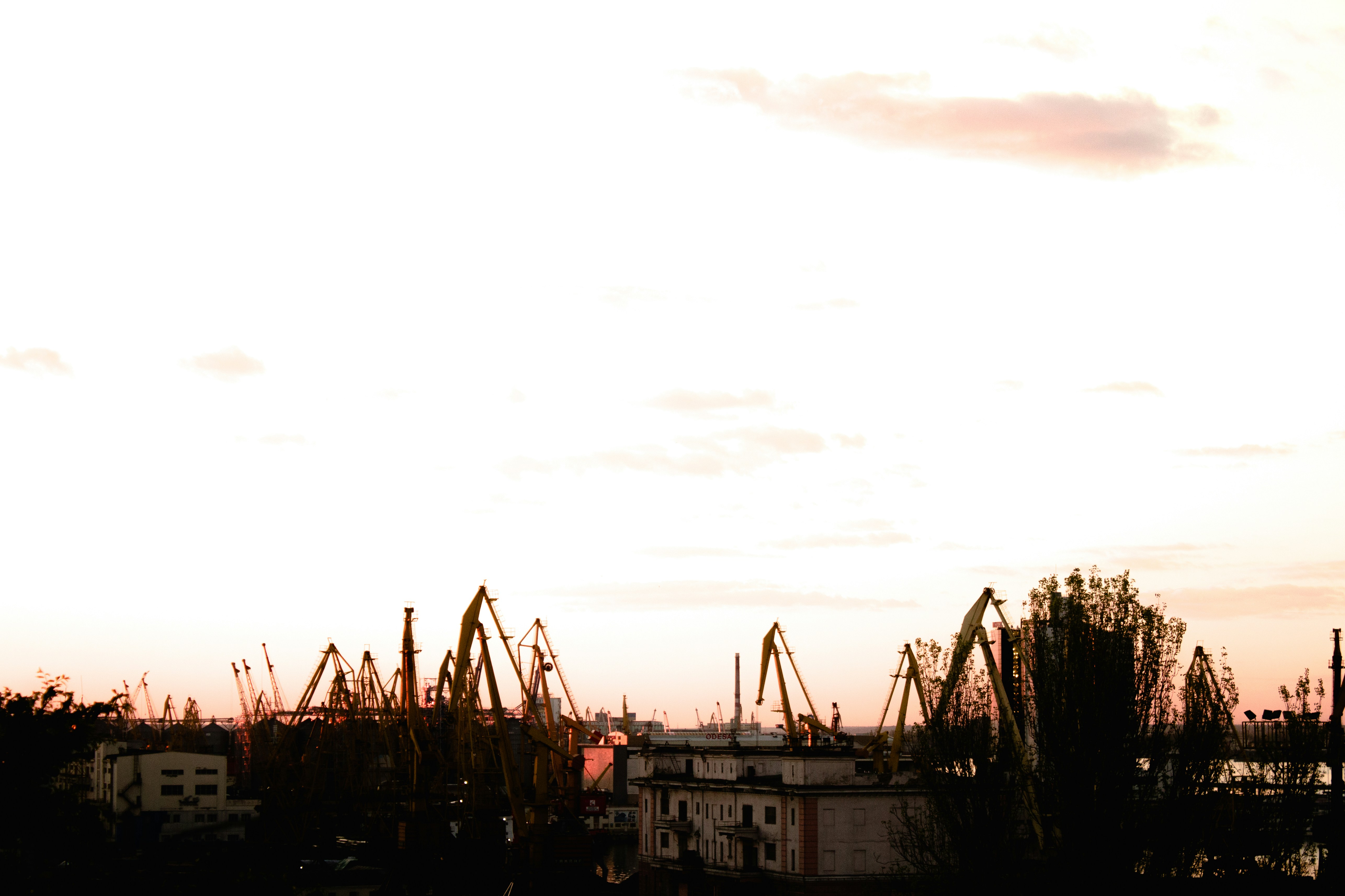 Dusk over the harbor: cranes in silhouette along the skyline