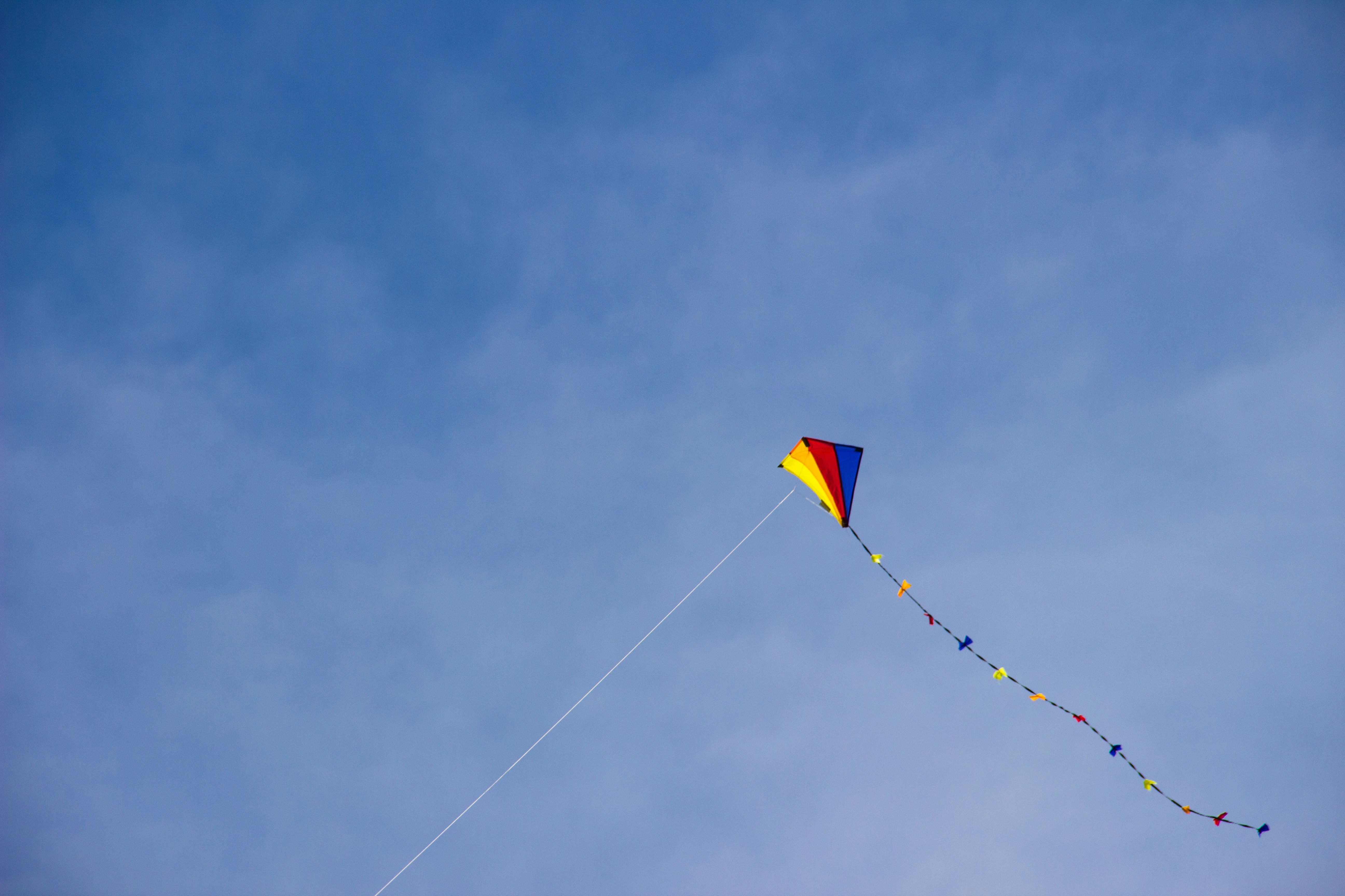 yellow and blue kite flying under blue sky during daytime