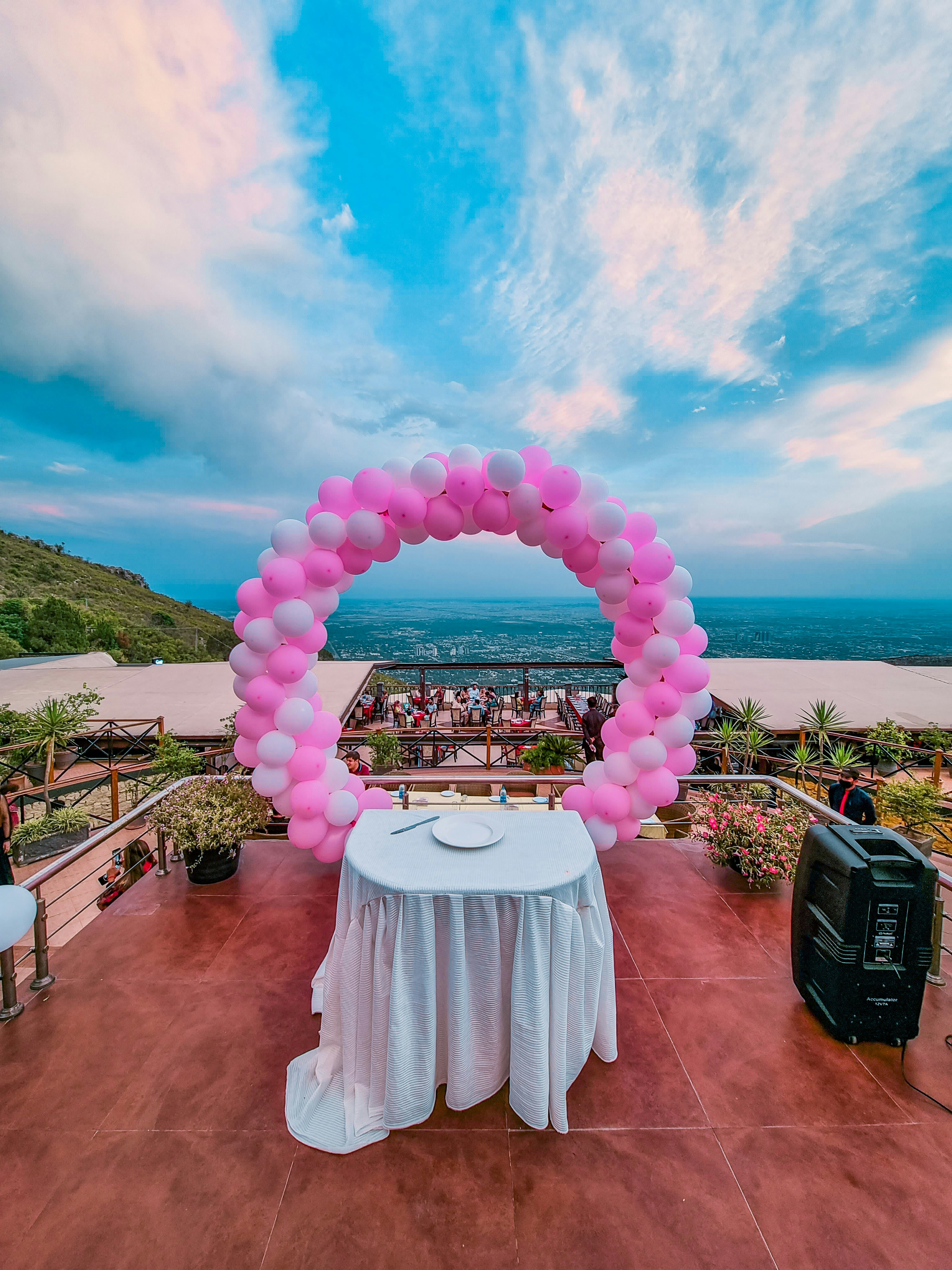 Pink Balloon Arch Framing a Scenic Terrace Overlooking a Distant City