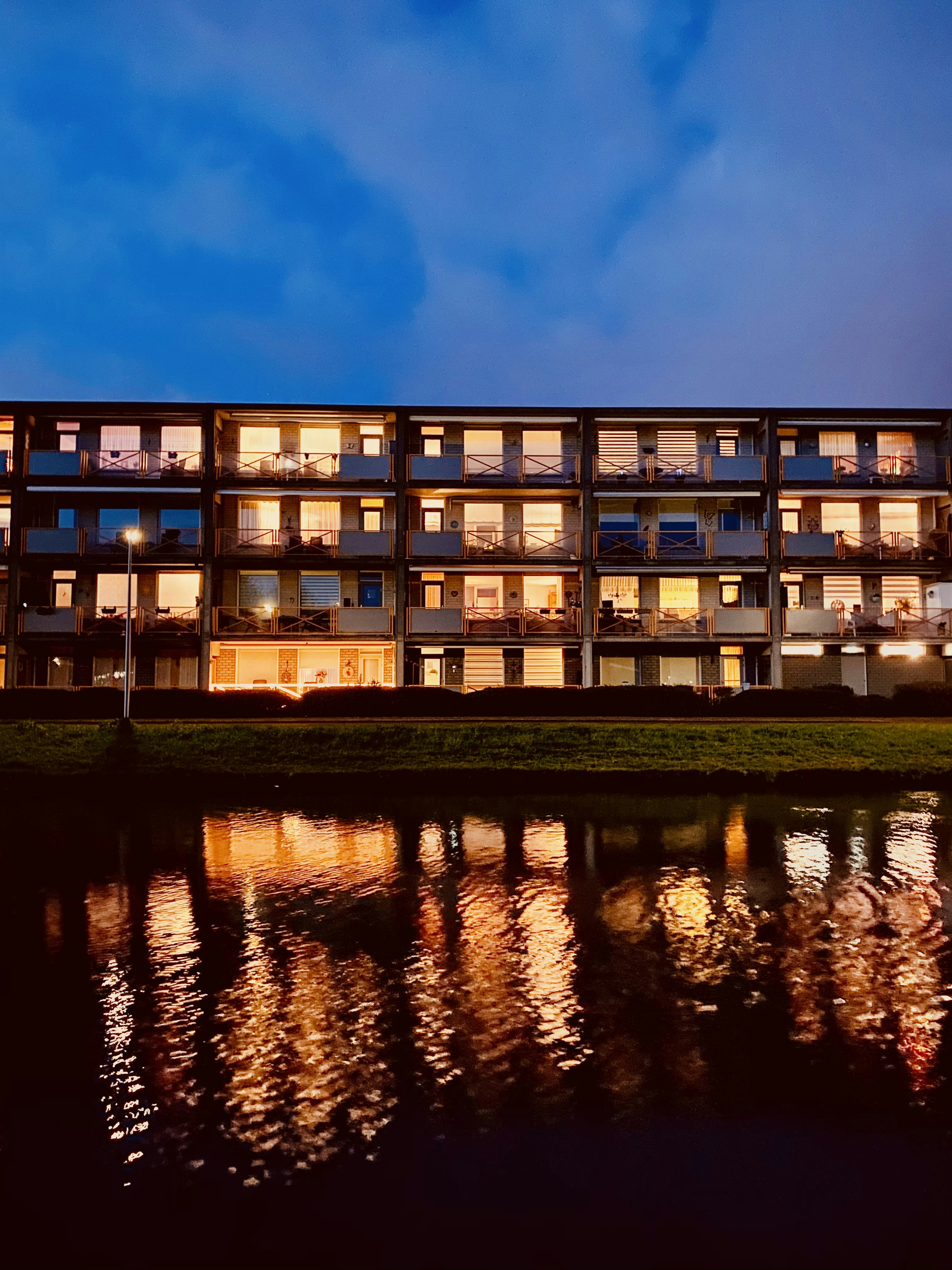Brown concrete building near body of water under blue sky during ...