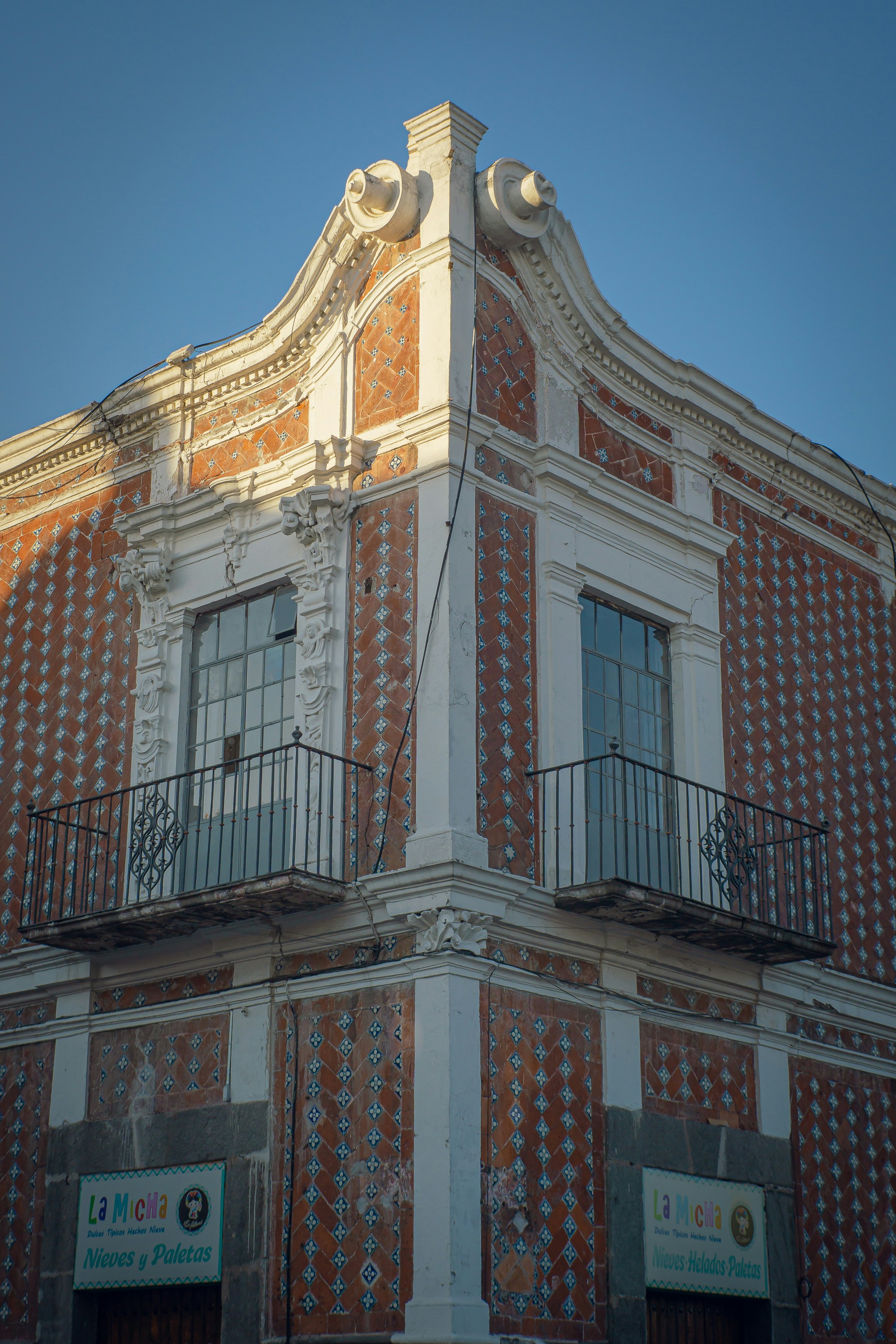 Sunlit Diamond-Tile Corner: A Historic Facade with Wrought-Iron Balconies