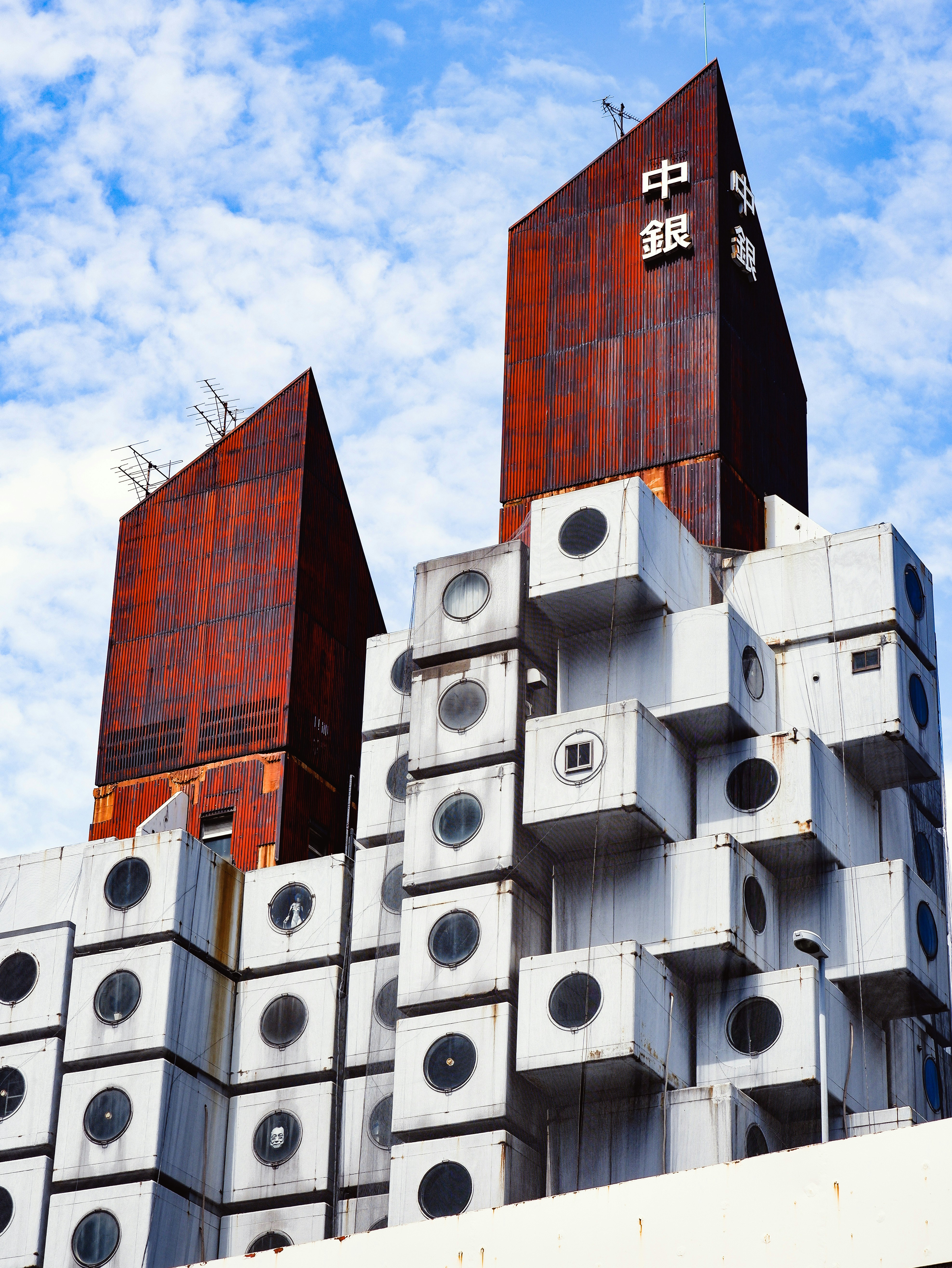 Unique modular building featuring distinct red towers and circular air conditioning units, showcasing innovative architecture. 