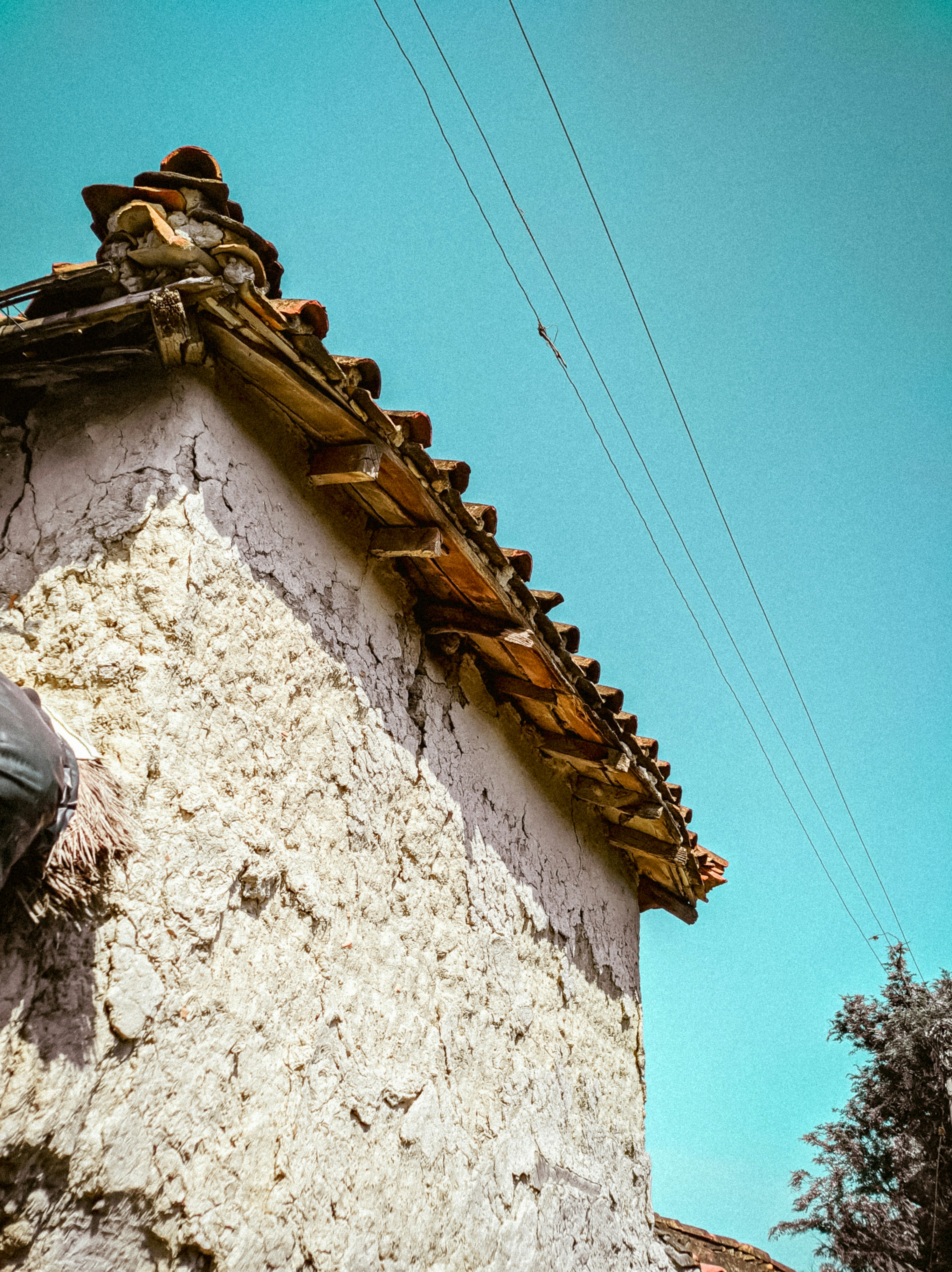 Close-up of a rustic building's roofline, showcasing traditional craftsmanship against a vibrant sky.