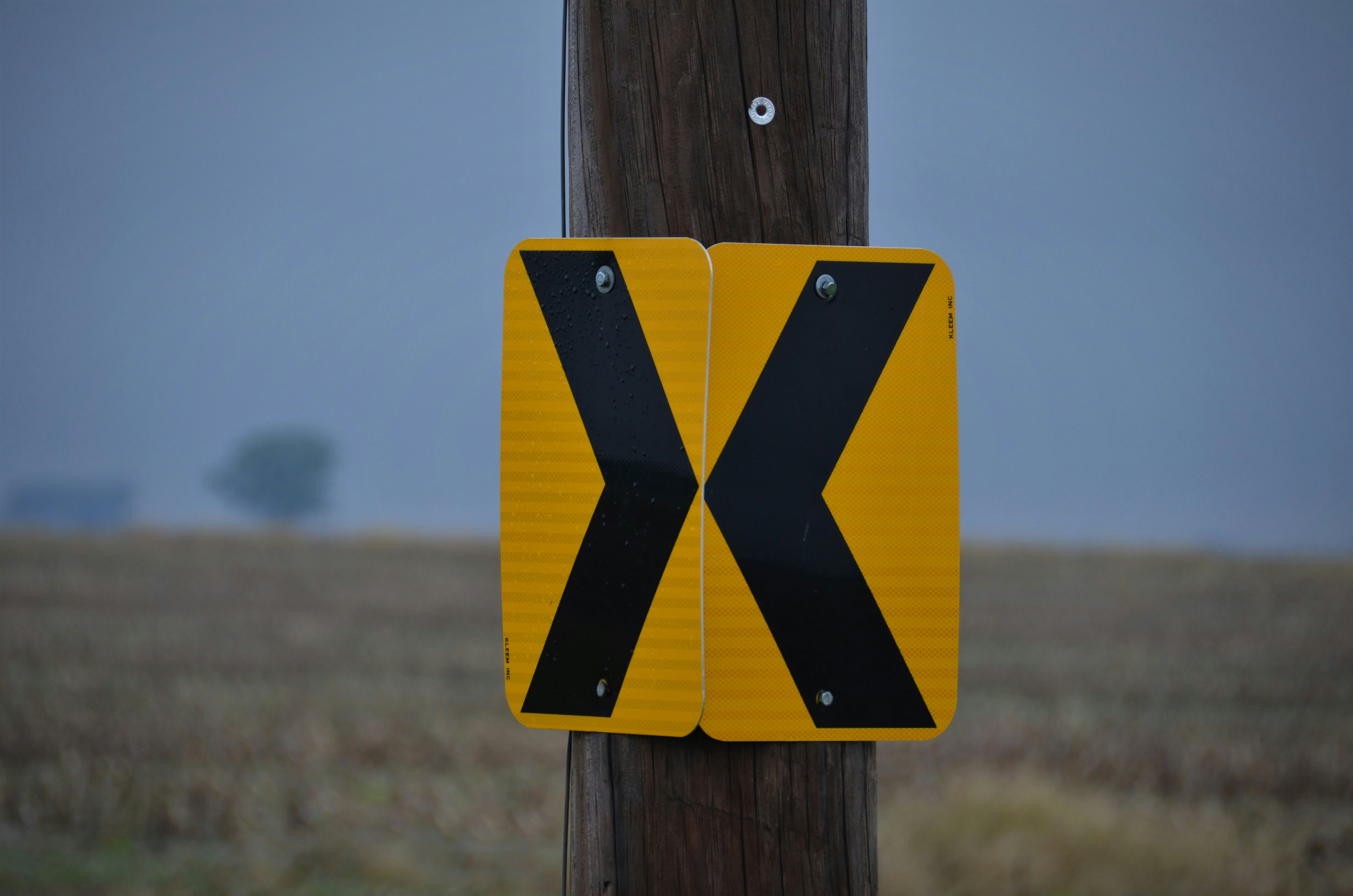 Dual Yellow X on a Weathered Post Framing an Open Horizon