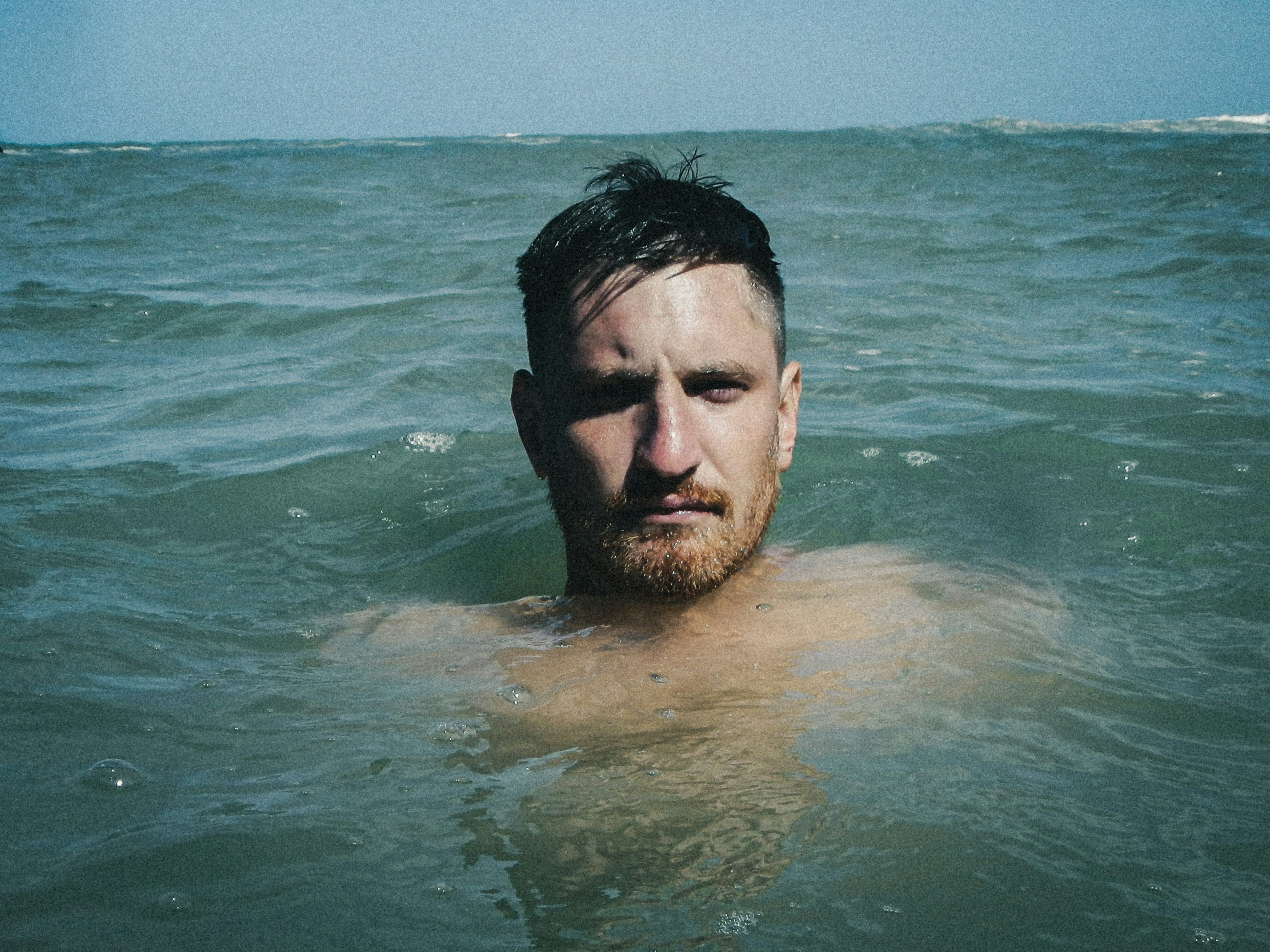 A man swimming in the ocean with his head in the water photo – Free ...
