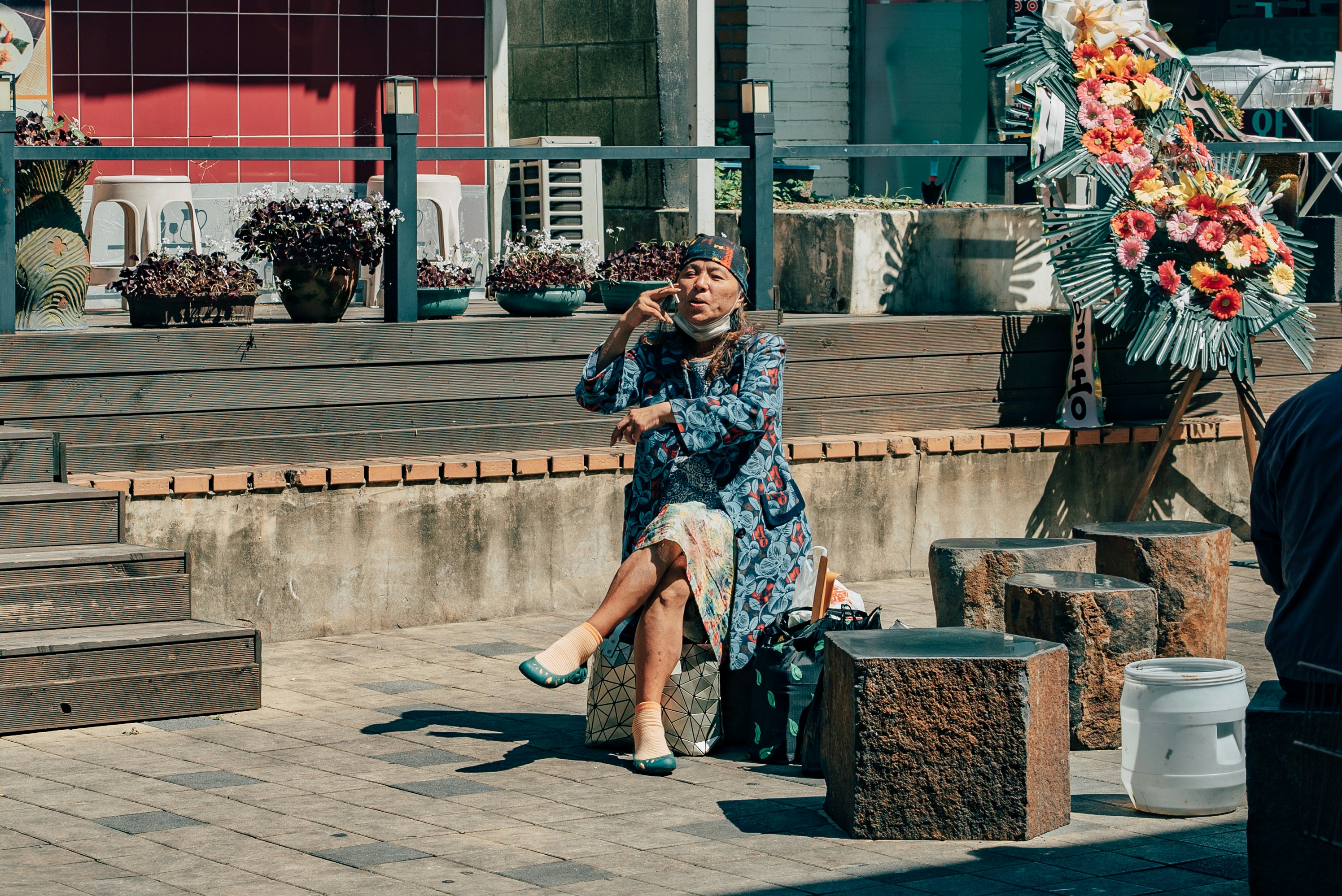 woman in black and white floral dress sitting on brown concrete bench during daytime