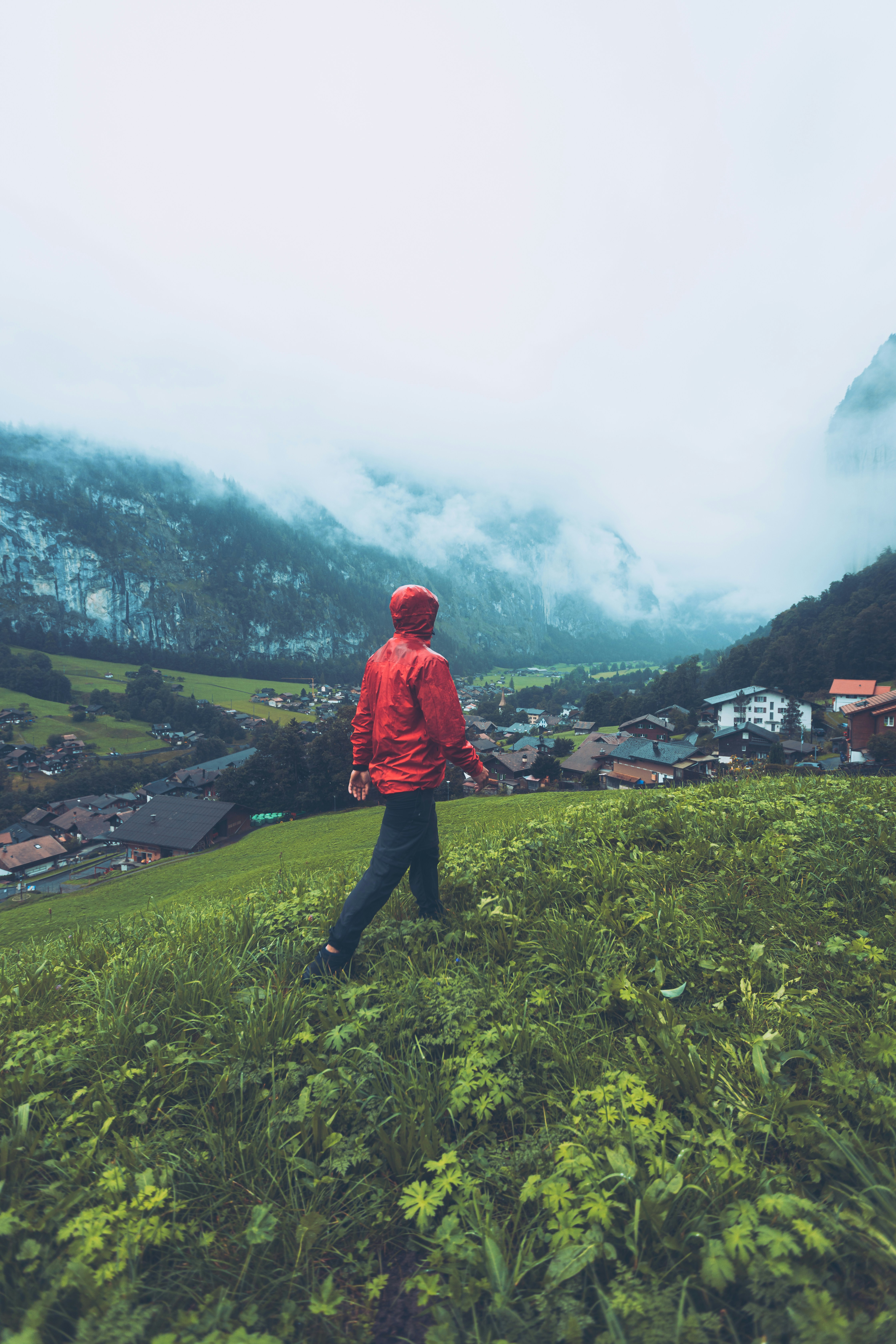 man in red hoodie standing on green grass field during daytime