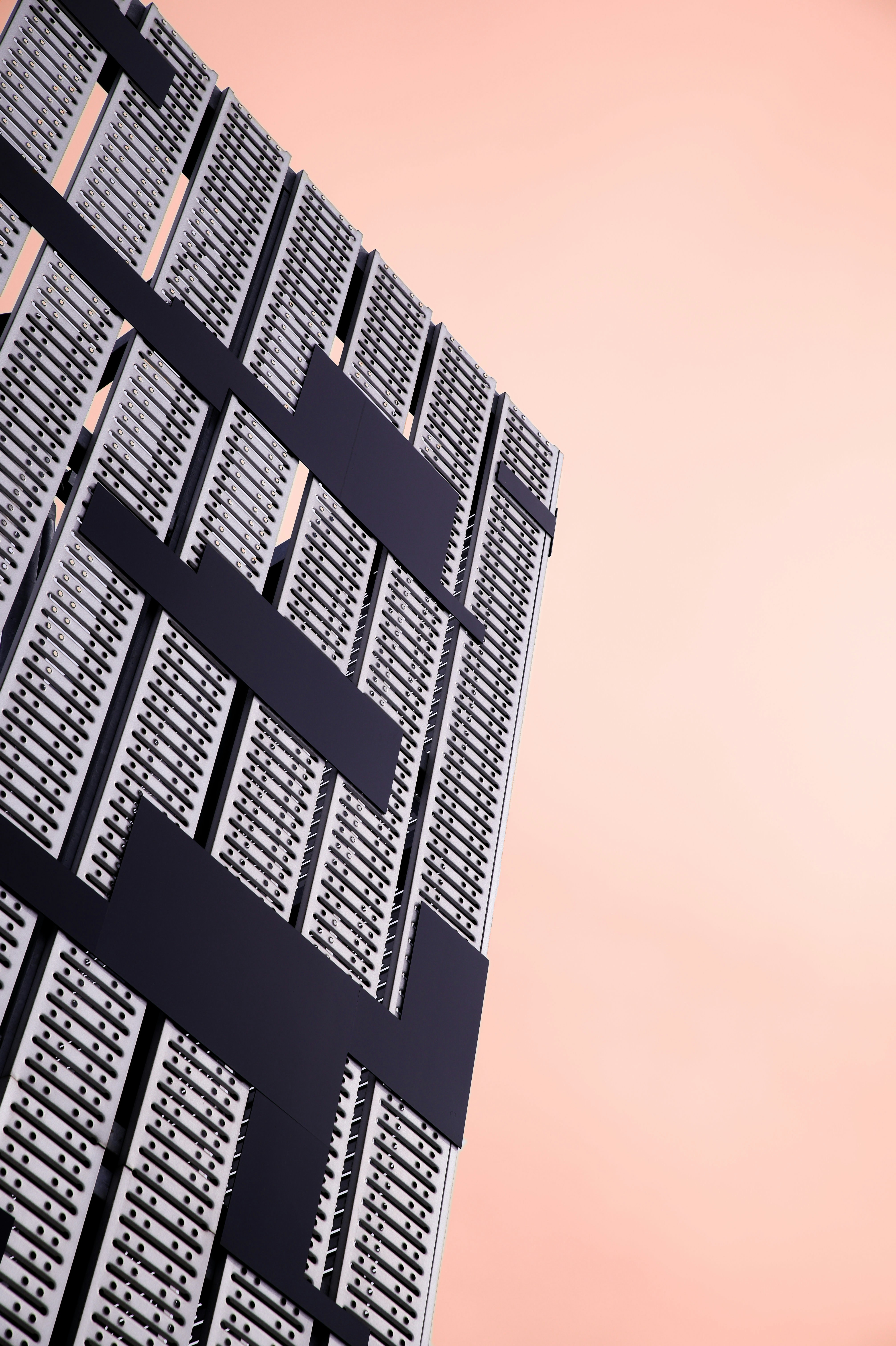 Tilted Facade: A Modern Grid Rising Against a Peach Sky