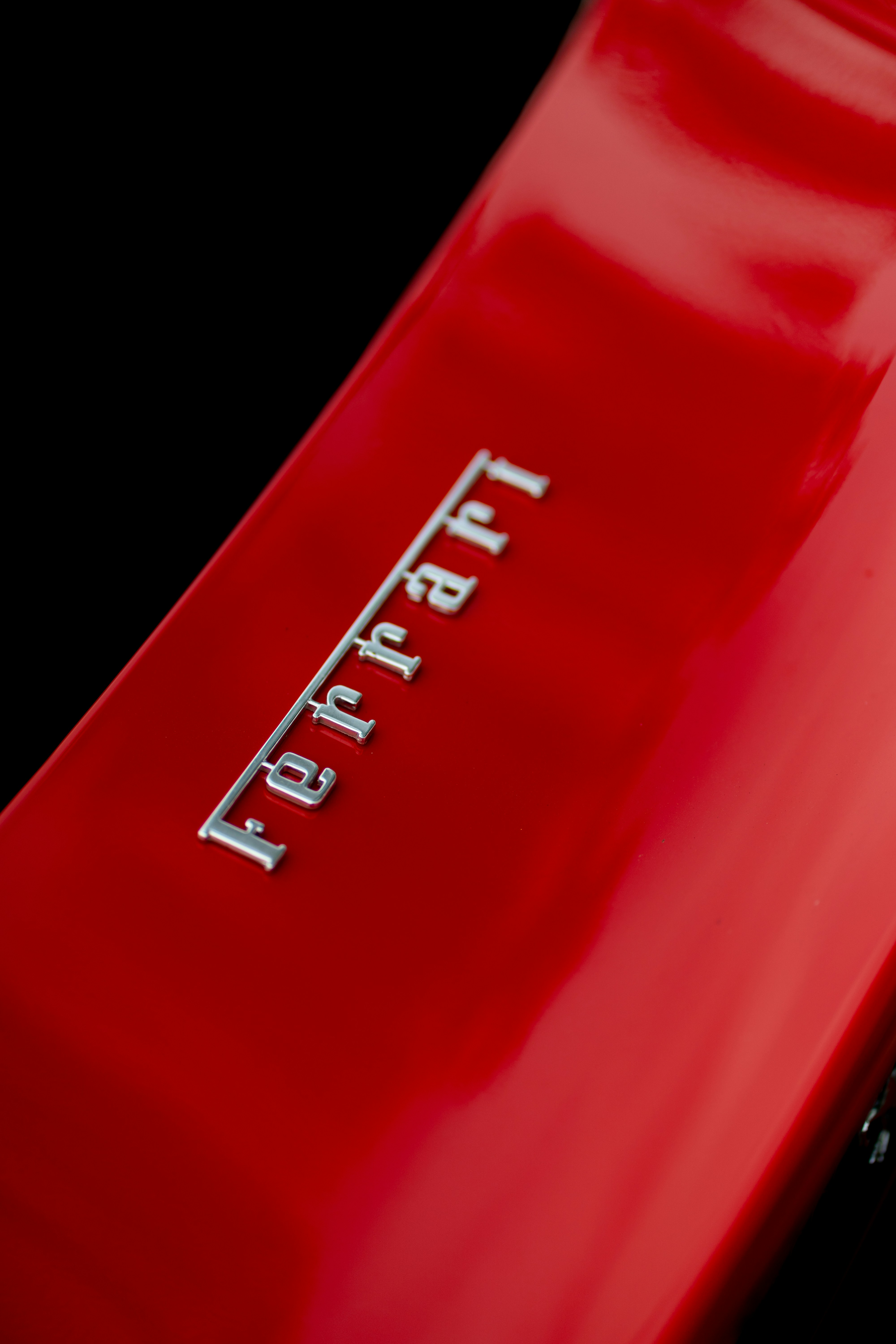 Chrome Script on a Crimson Curve: Ferrari Badge Close-Up