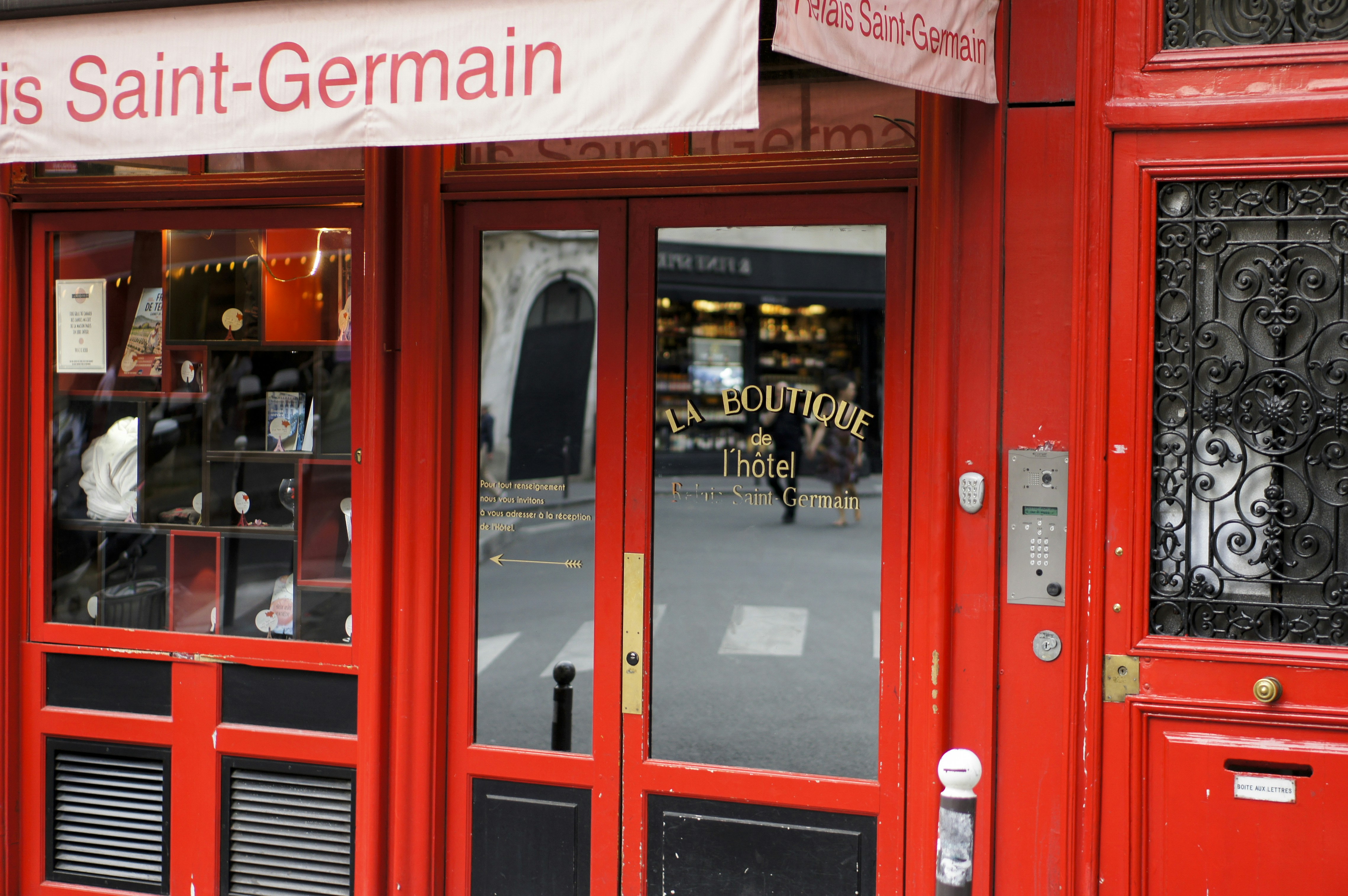 Red storefront of La Boutique, featuring elegant signage and a glimpse of the interior products. The inviting design reflects the essence of Parisian charm.