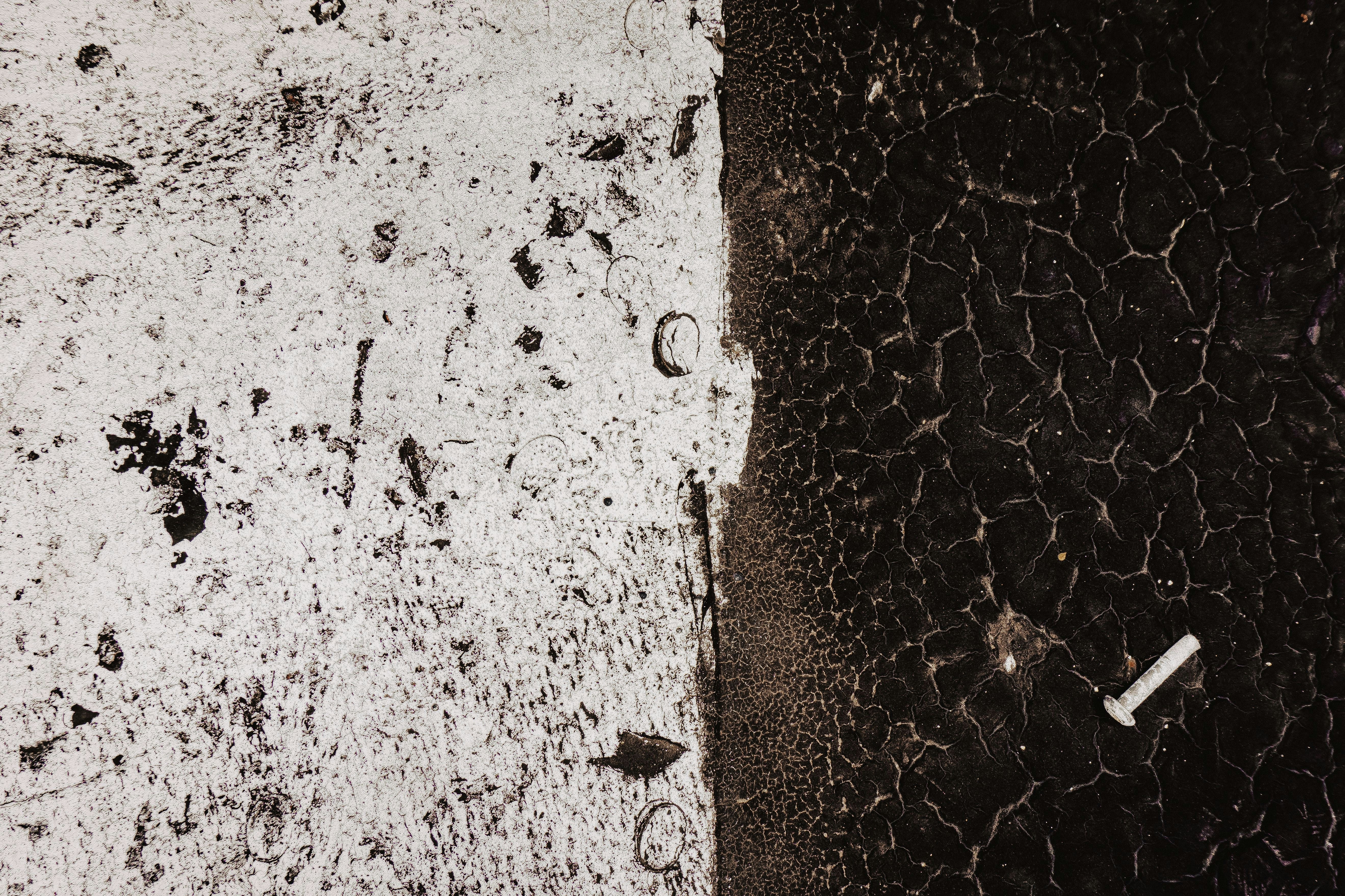 Aerial view of juxtaposed white and black rooftop surfaces, with cracks and debris.