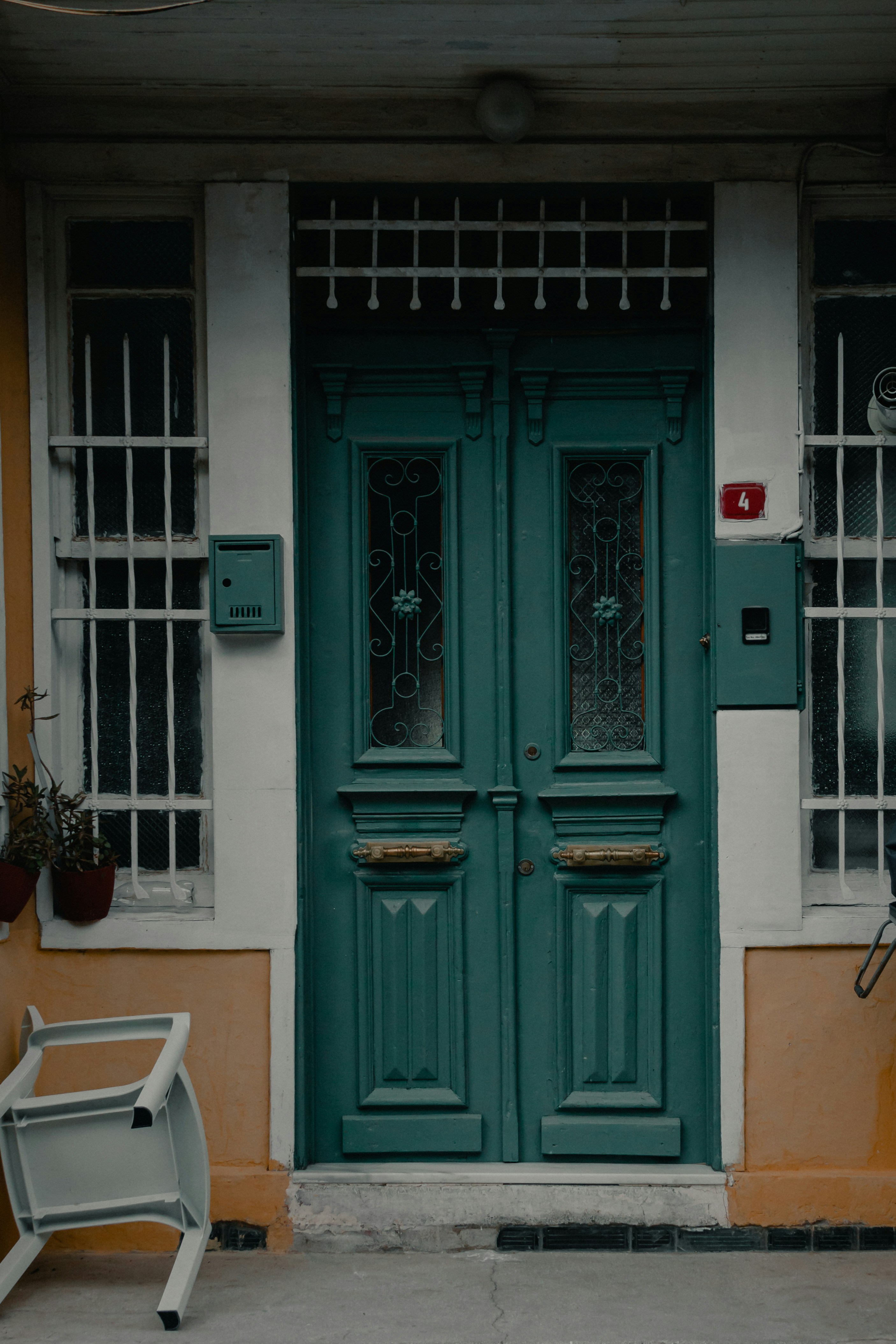 Teal Entryway with Ornate Ironwork on a Weathered Urban Facade