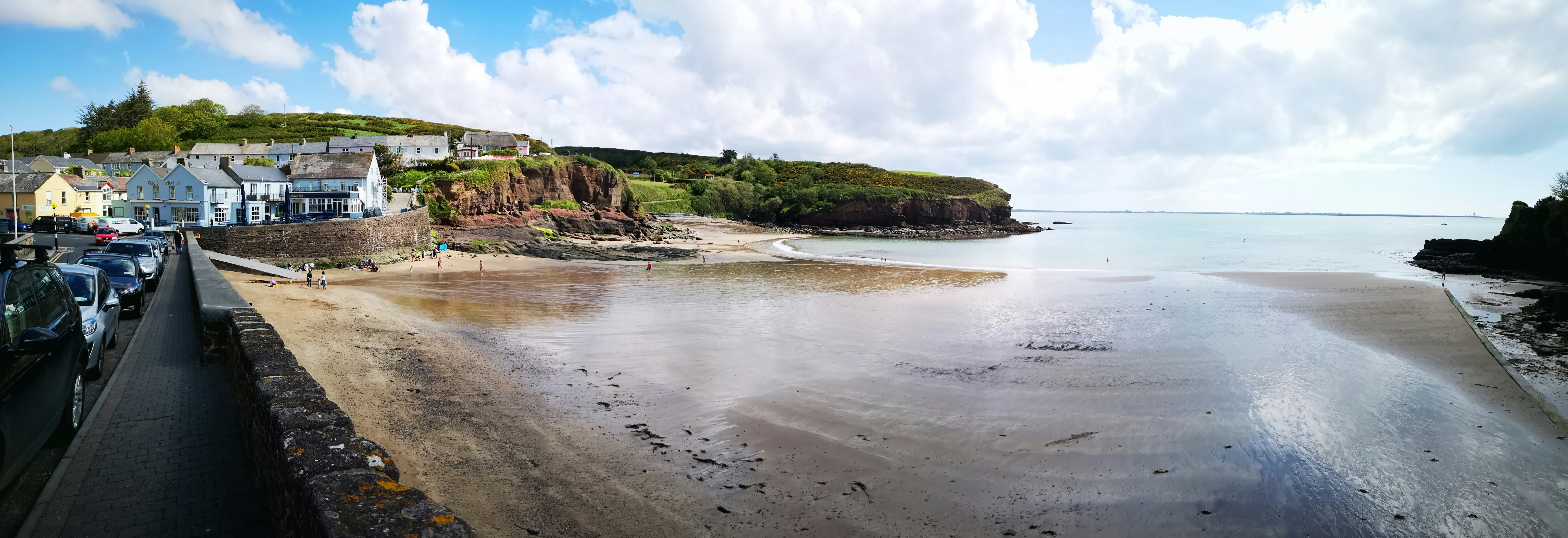 Quiet seaside village with sandy beach and calm waters under a bright sky.
