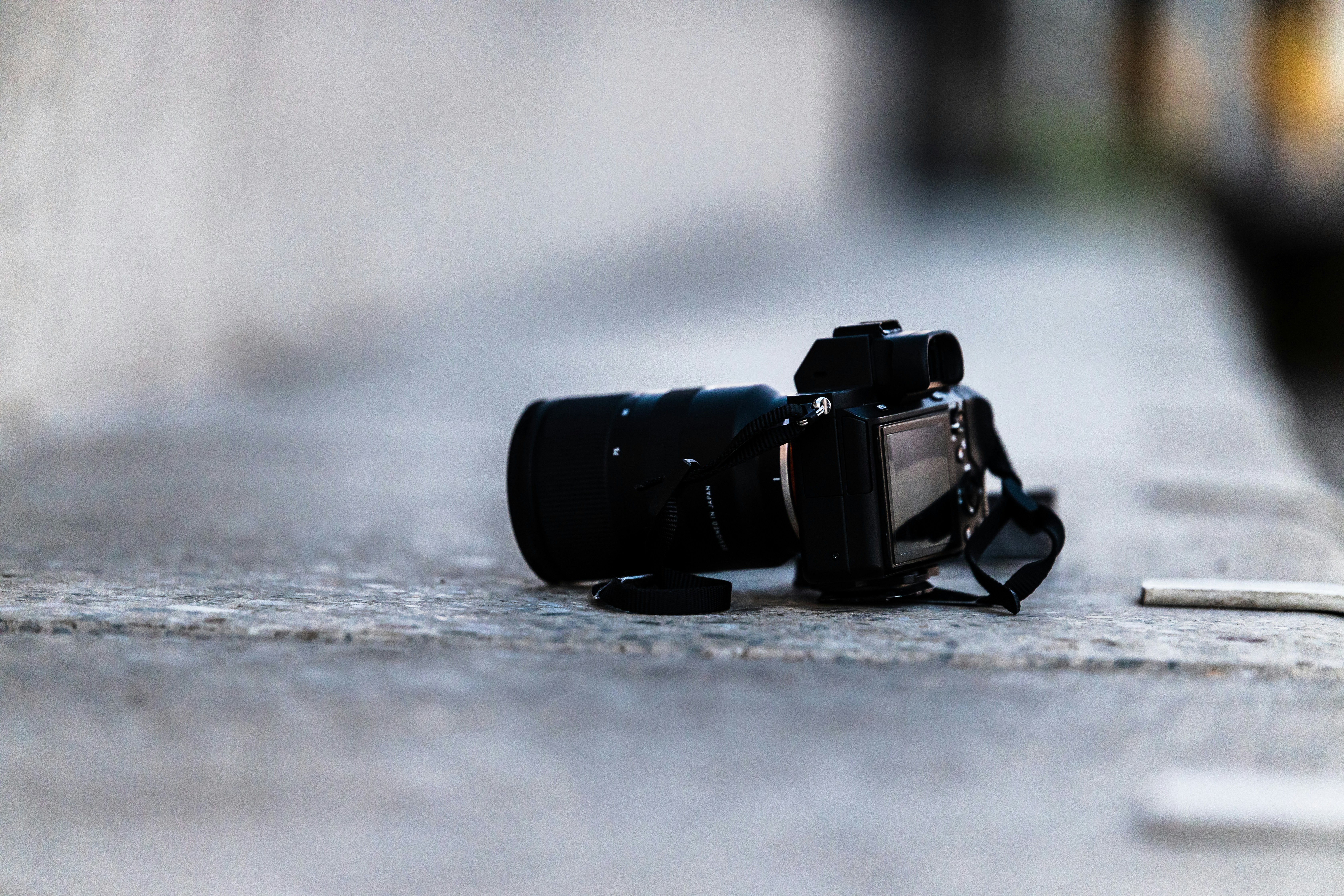Canon EOS R camera resting on a concrete surface, showcasing its sleek design and ready for the next shot.