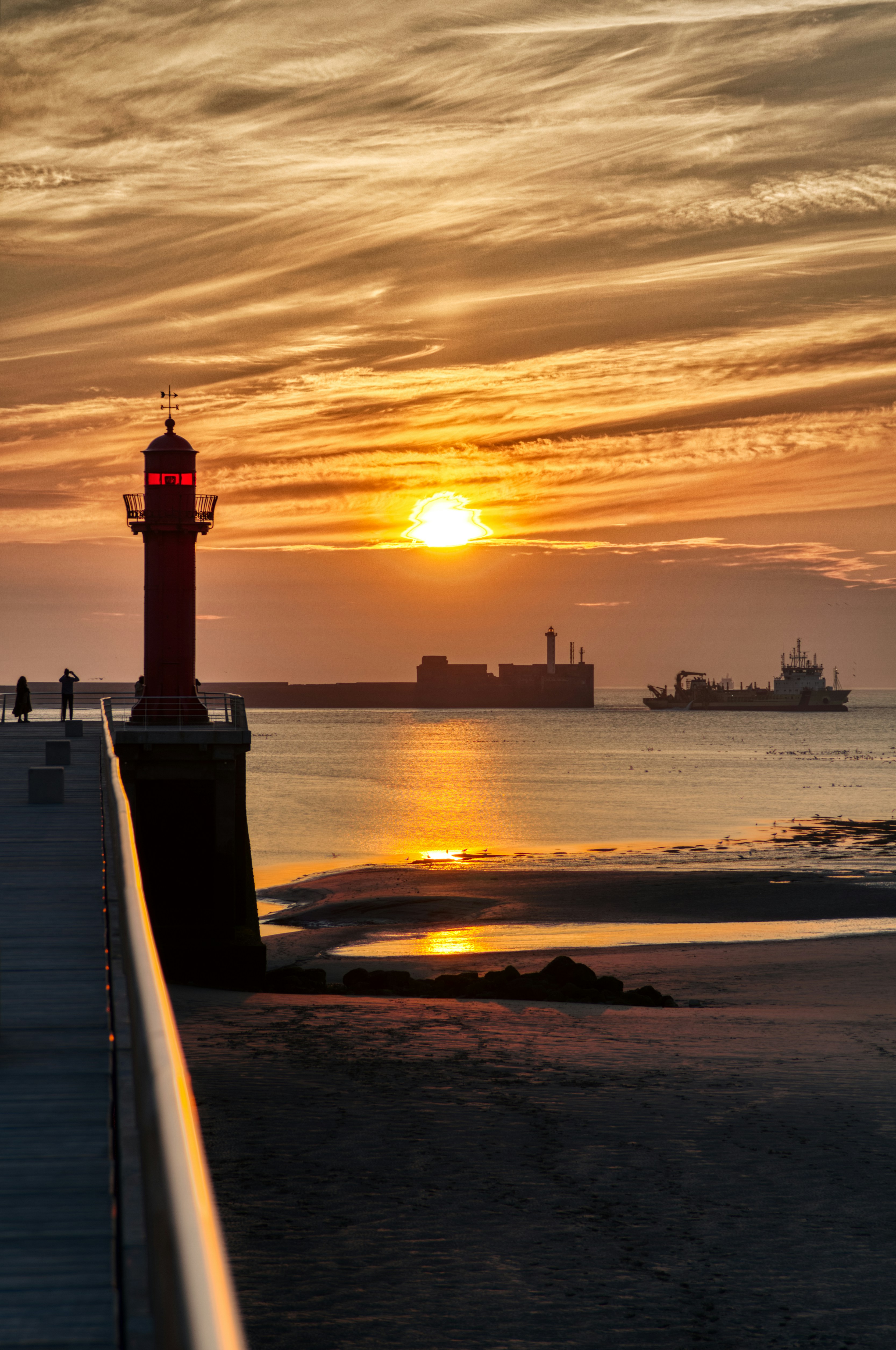 Sunset Beacon: A Pier-Top View with a Red Lighthouse Silhouette