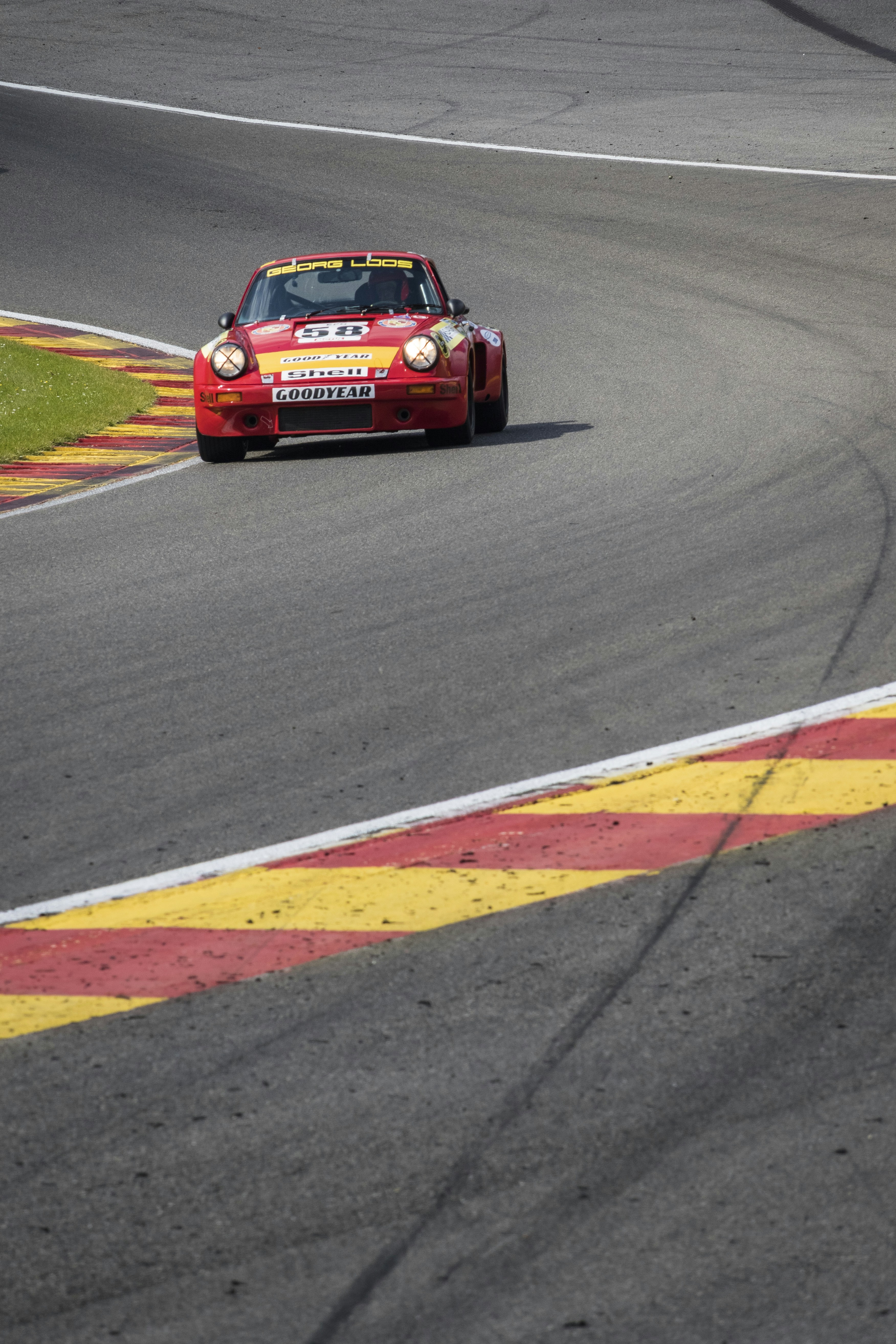 Porsche 911 race car shot during the Spa Classic event (2018)– Circuit de Spa-Francorchamps, Belgium | a red car driving down a race track