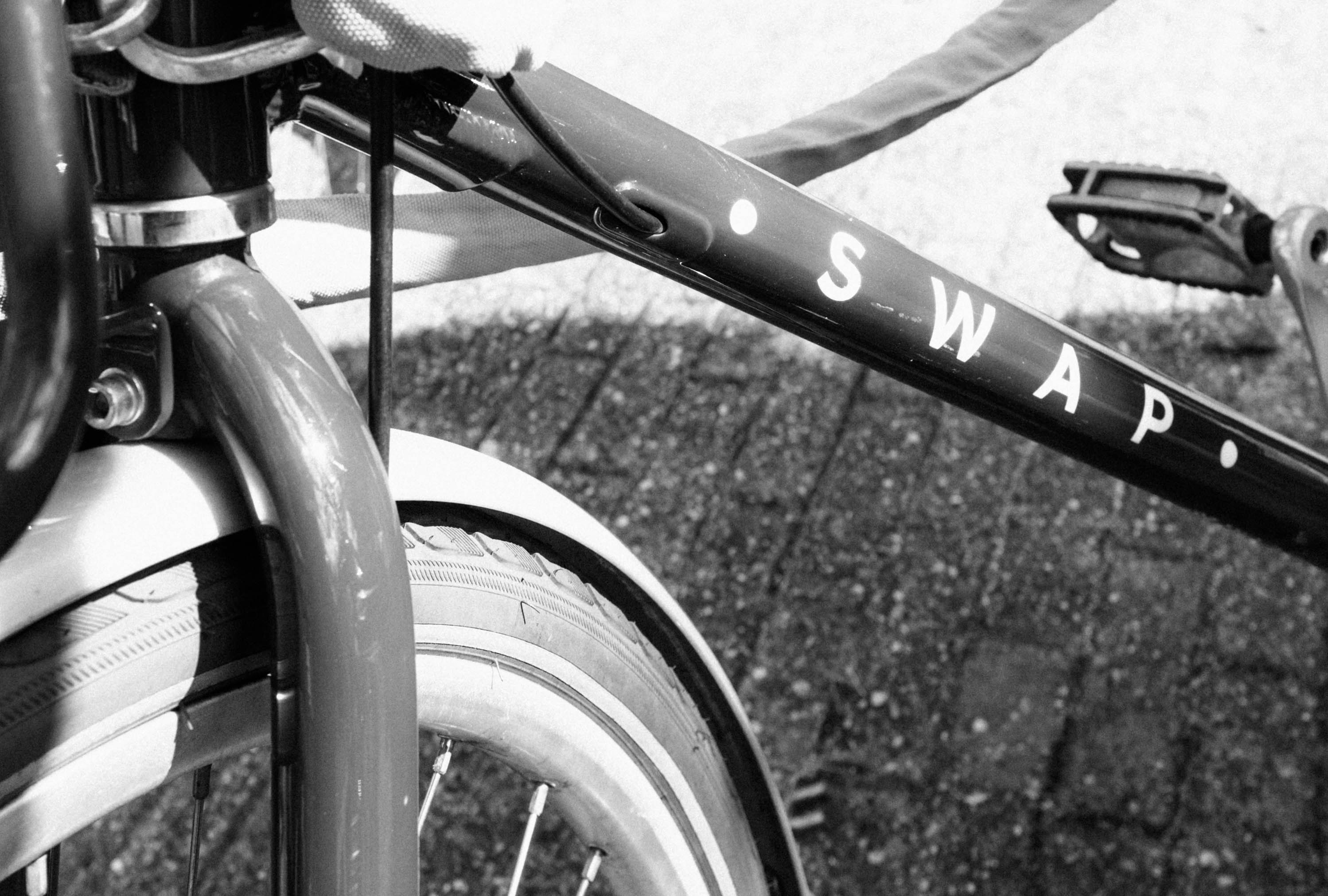 Close-up of a bicycle frame featuring the word 'SWAP,' emphasizing the concept of bike sharing in an urban setting.