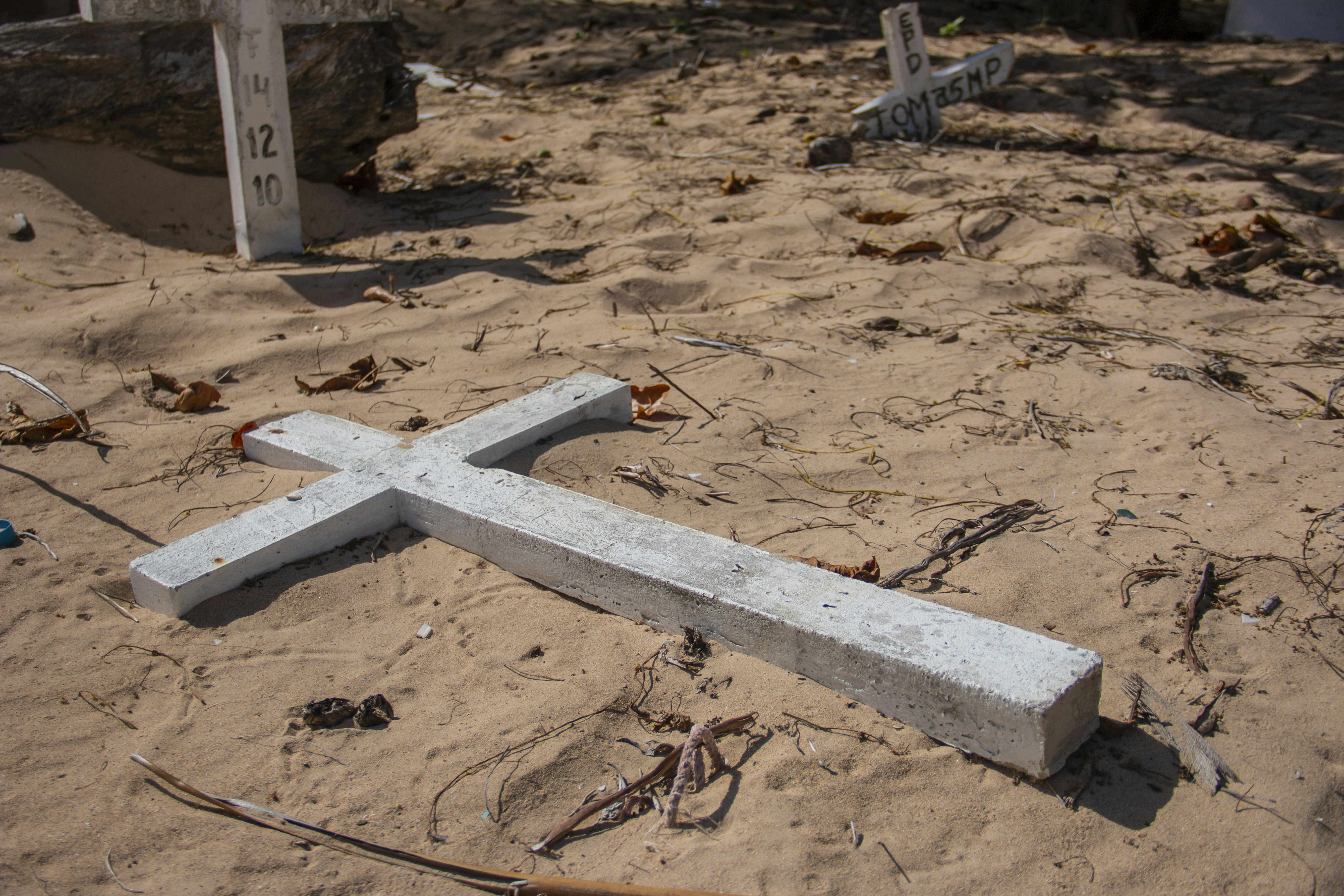 A cement cross laying in the sand on a beach photo – Free Playa Image ...