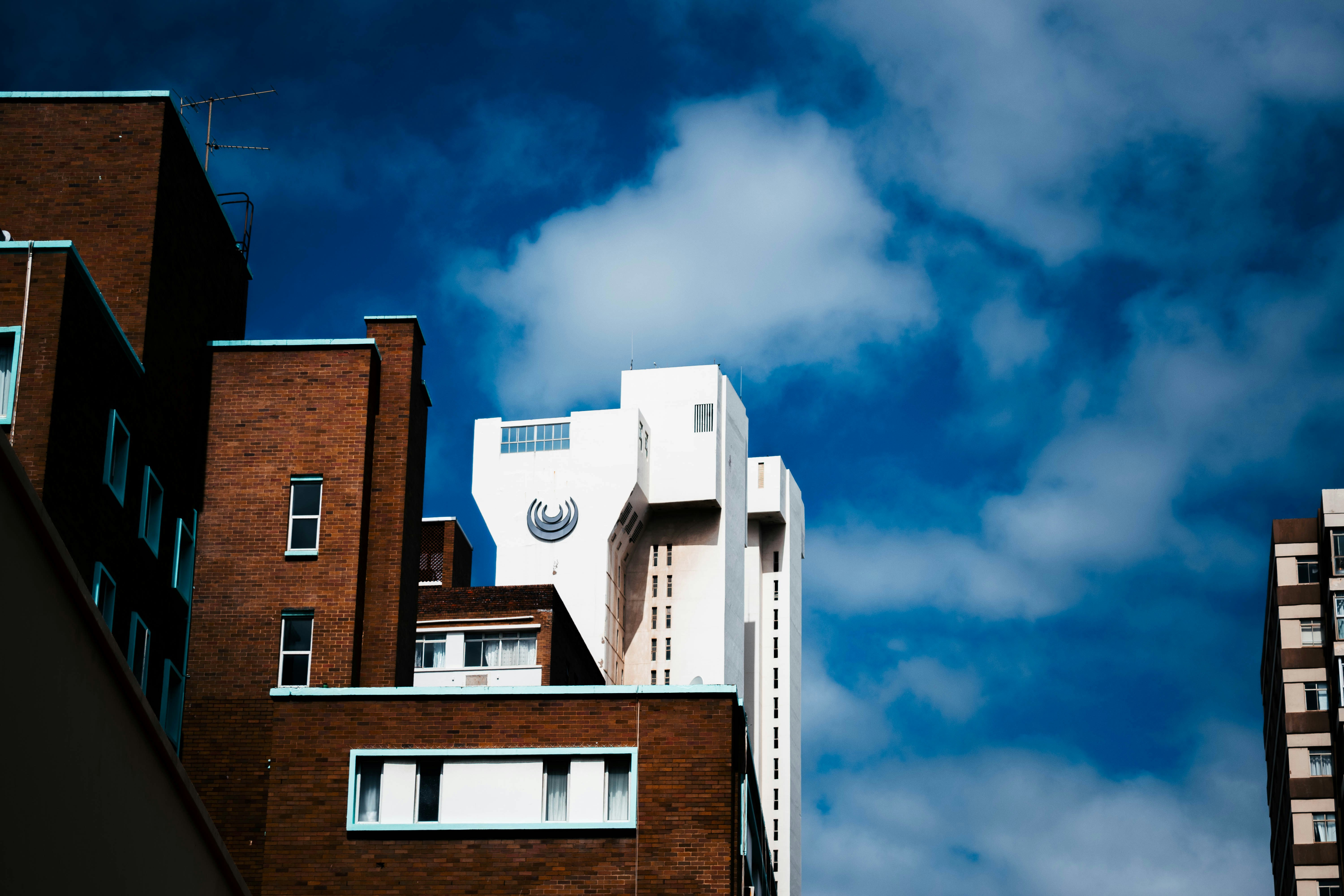 Brick and white buildings rise against a vibrant blue sky with scattered clouds.