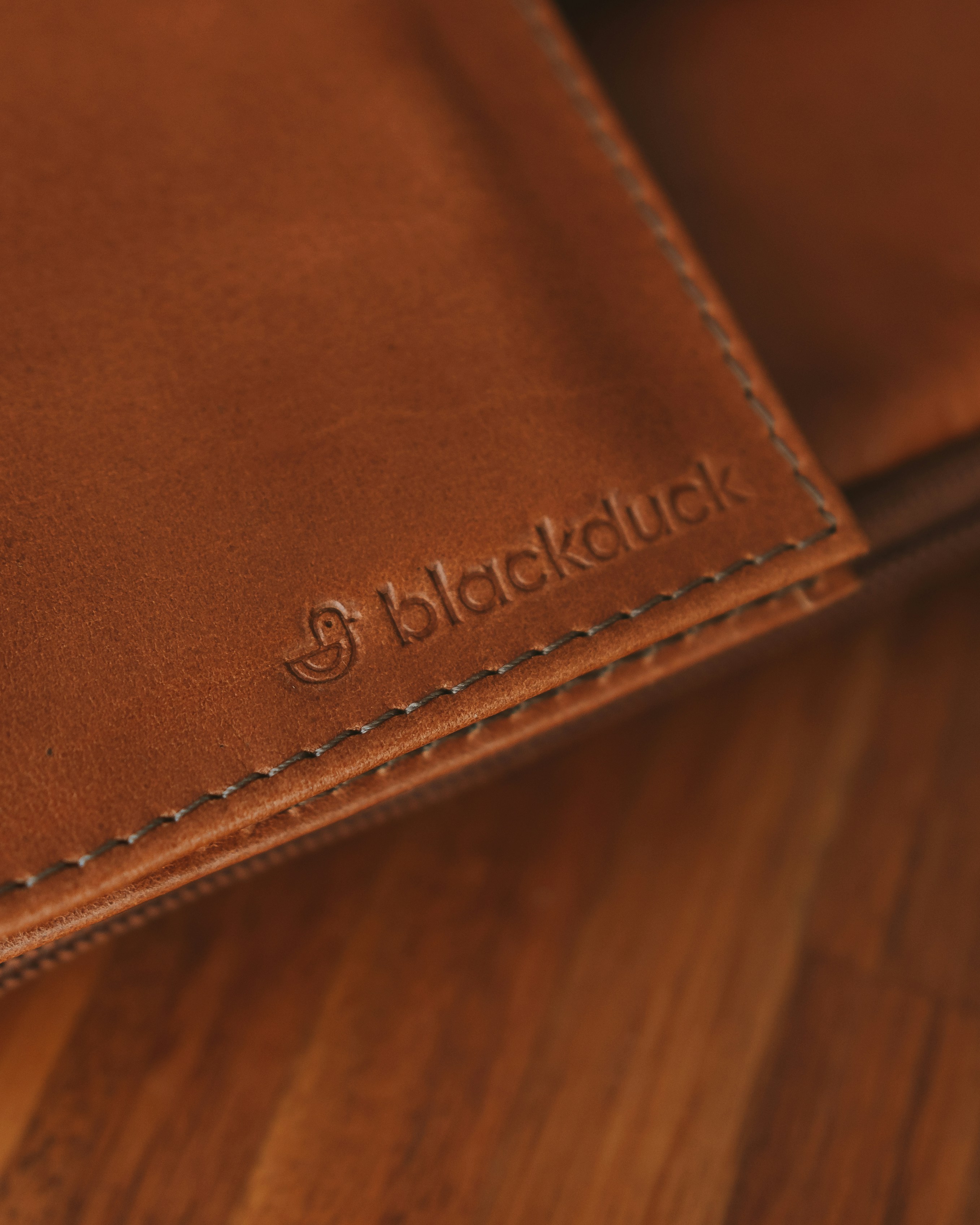 Close-up of a beautifully stitched leather wallet featuring the embossed 'blackduck' logo. The rich texture highlights the craftsmanship involved.