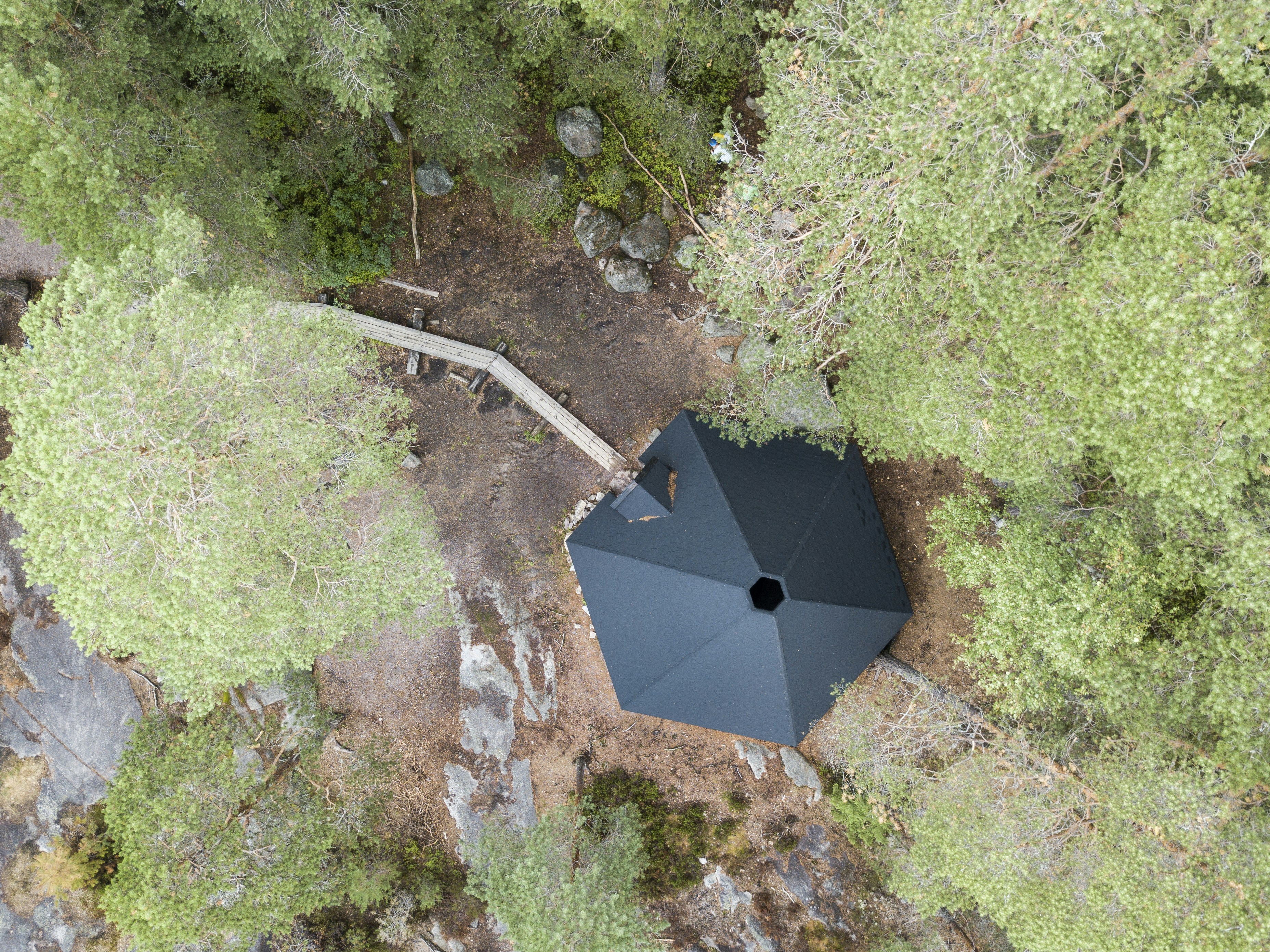 A Kota in Nuuksio National Park, seen from above. | a black umbrella sitting in the middle of a forest