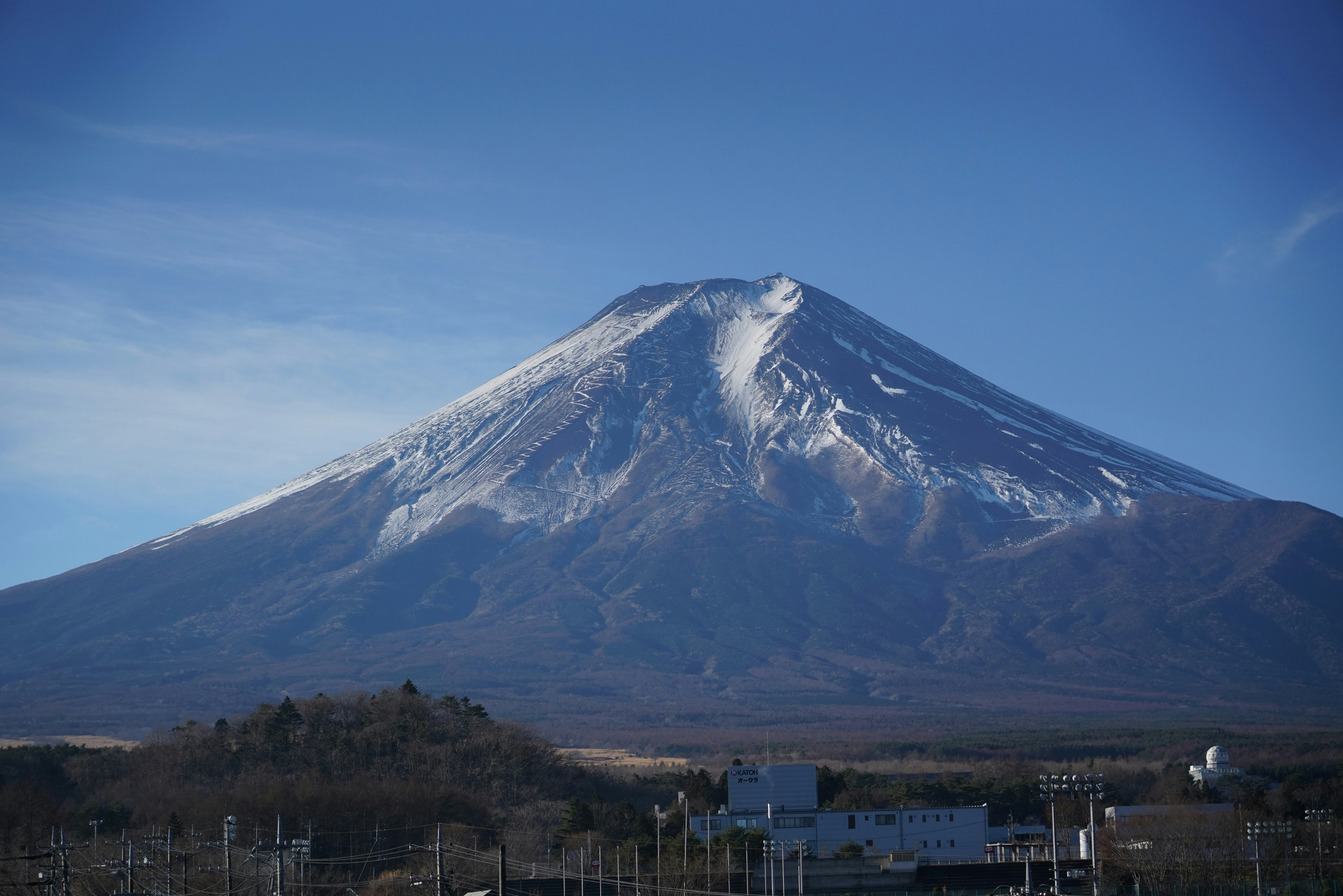 Snow-capped mountain looming above a city with clear blue skies.
