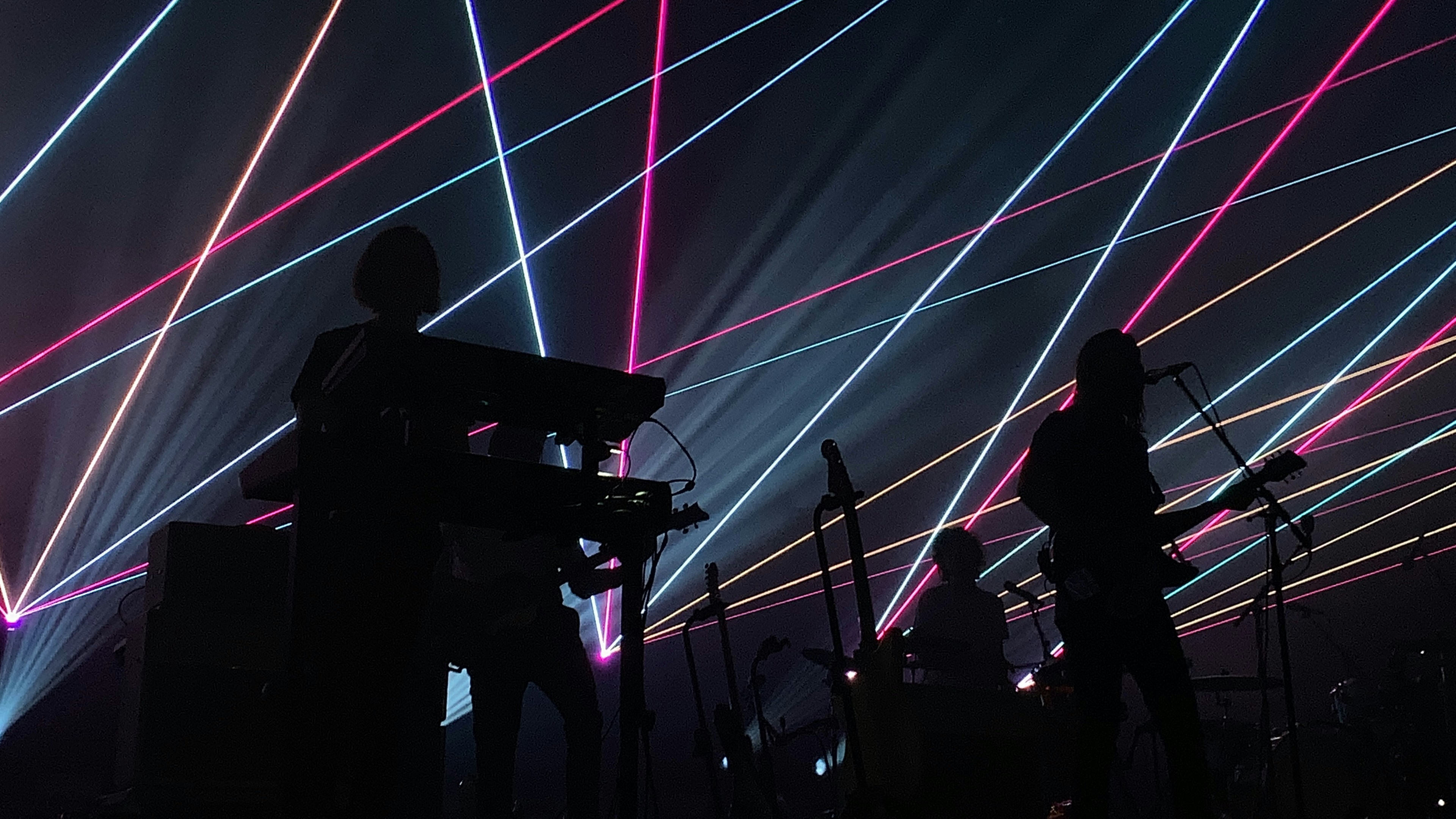 A band performing on stage with laser lights in the background photo ...