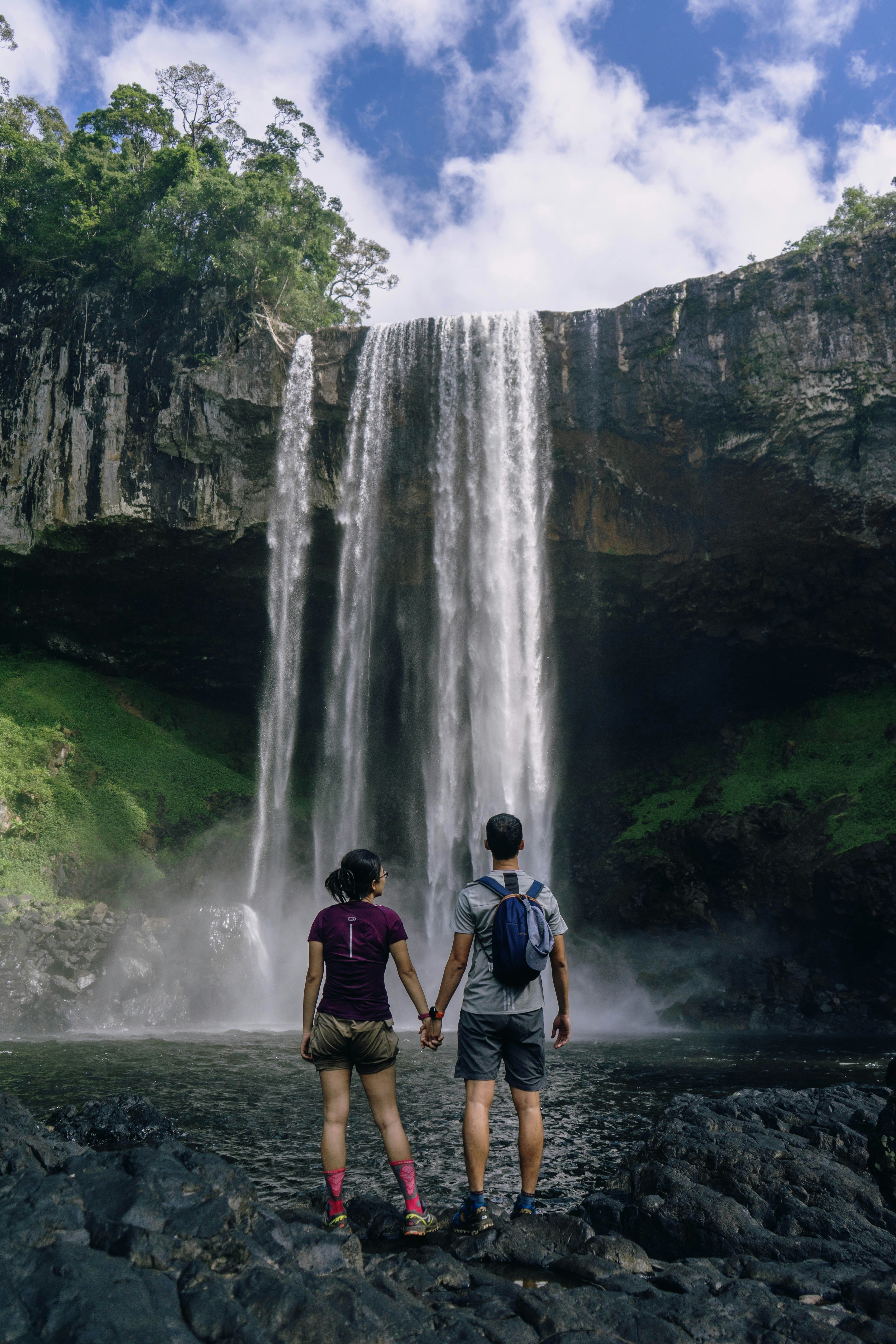 Two Travelers Hold Ground Before a Majestic Cascade