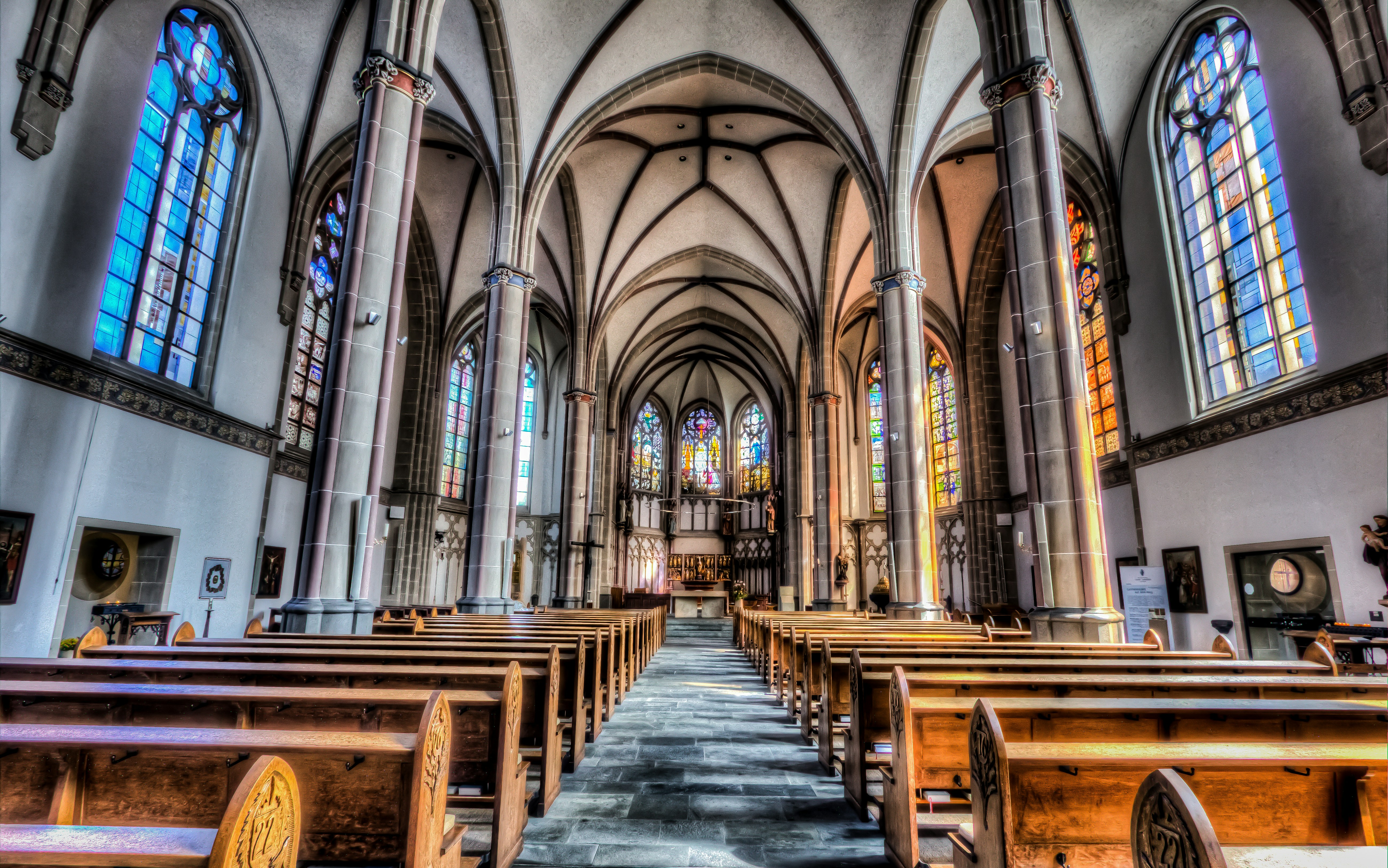 Gothic cathedral interior with soaring arches and colorful stained glass windows.