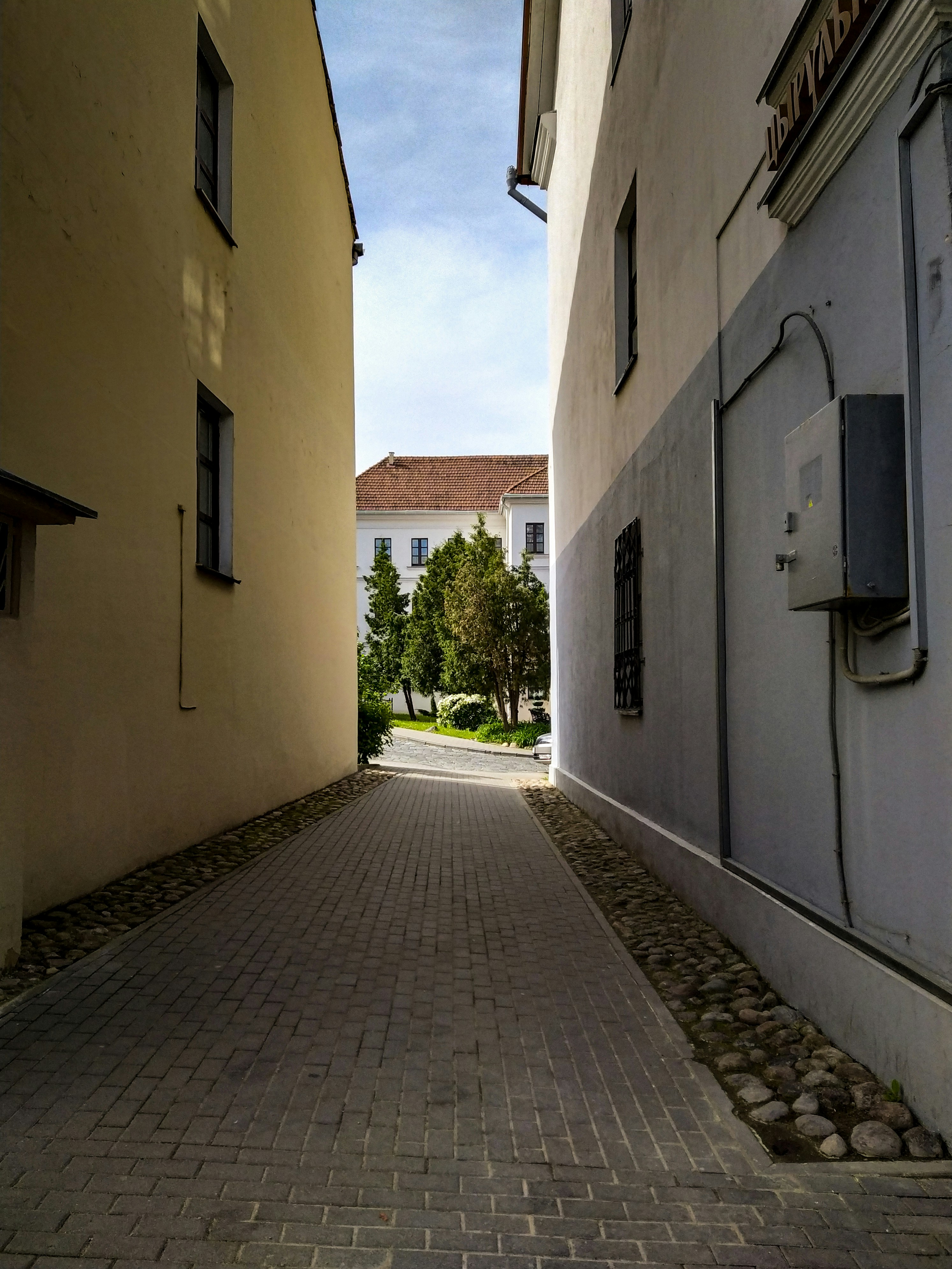 An alley way with a clock on the side of it photo – Free Street Image ...