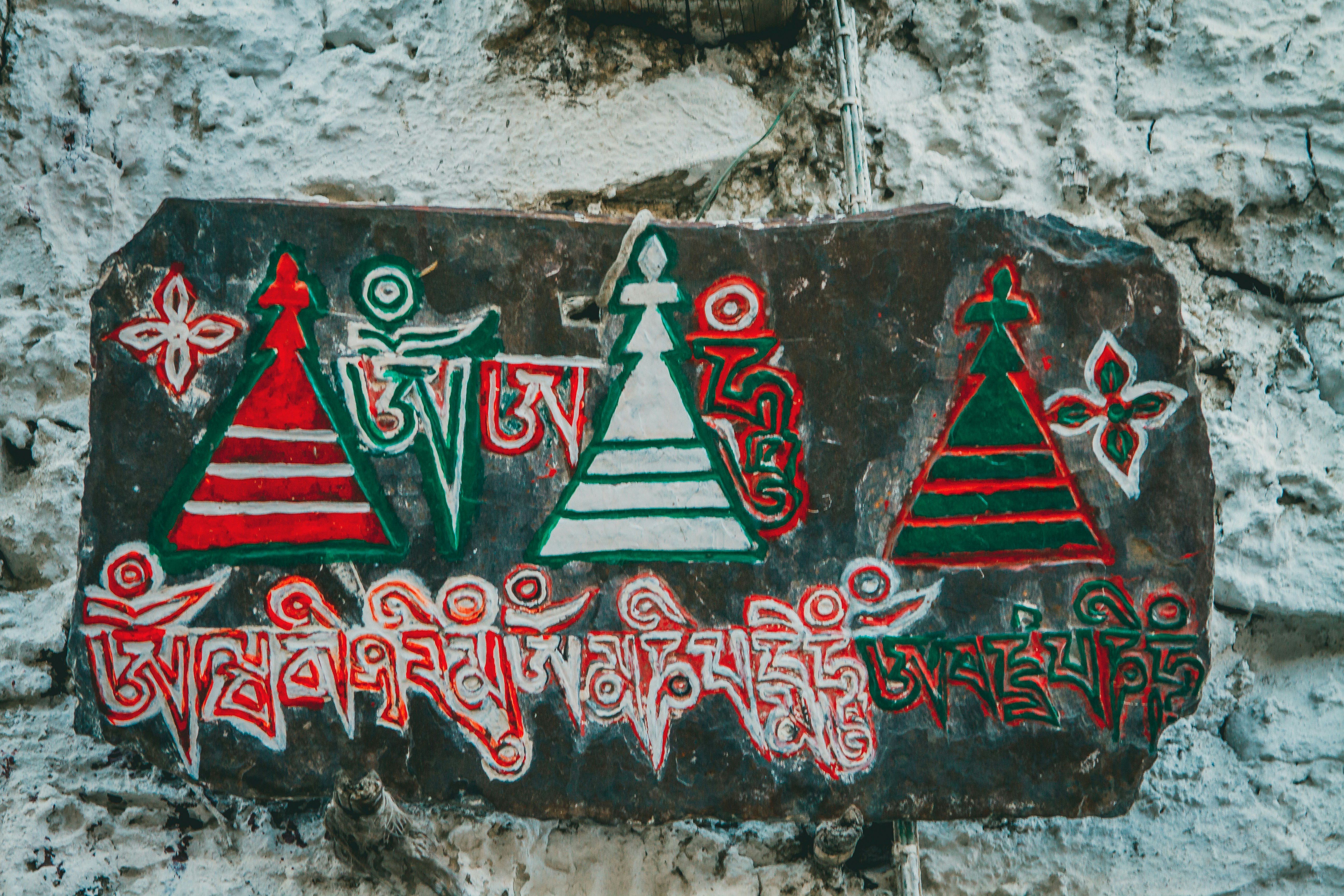 Three Stylized Trees flanking Tibetan Script on a Weathered Stone Plaque