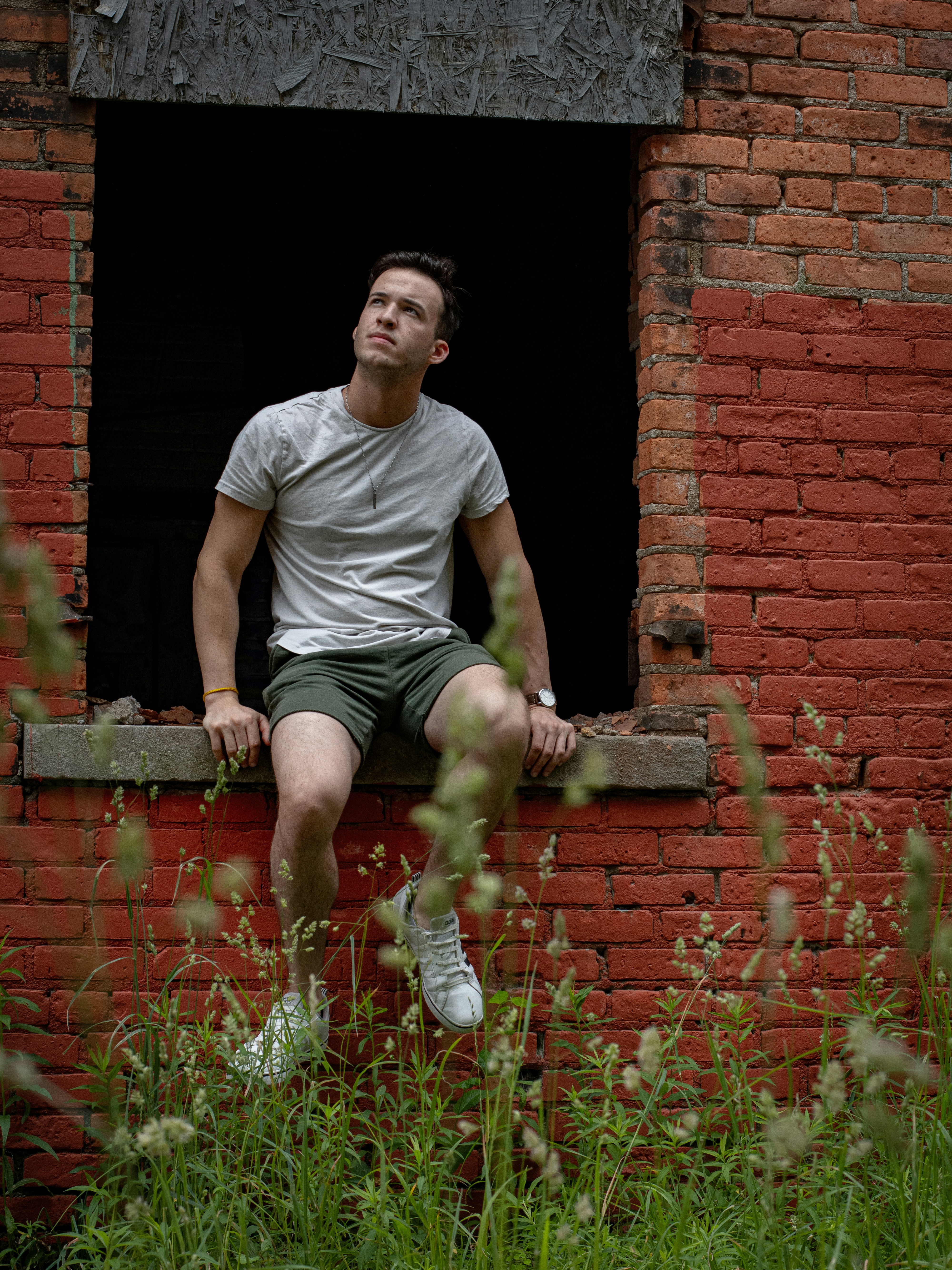 Threshold of Red Brick: A Quiet Figure Among Wild Grass