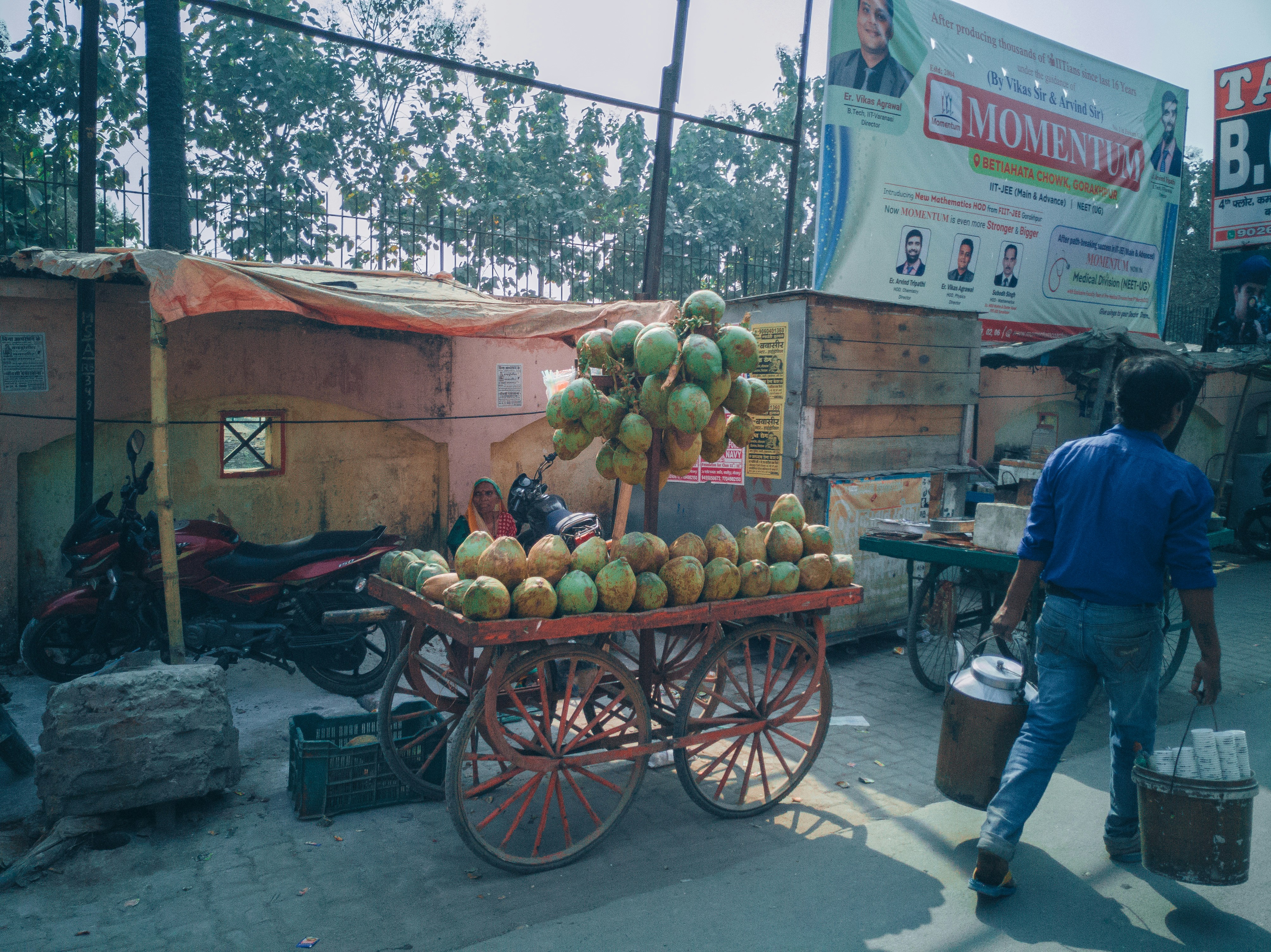 A bustling street vendor cart filled with coconuts, surrounded by urban scenery and passersby. The scene captures the essence of local commerce and community interaction.