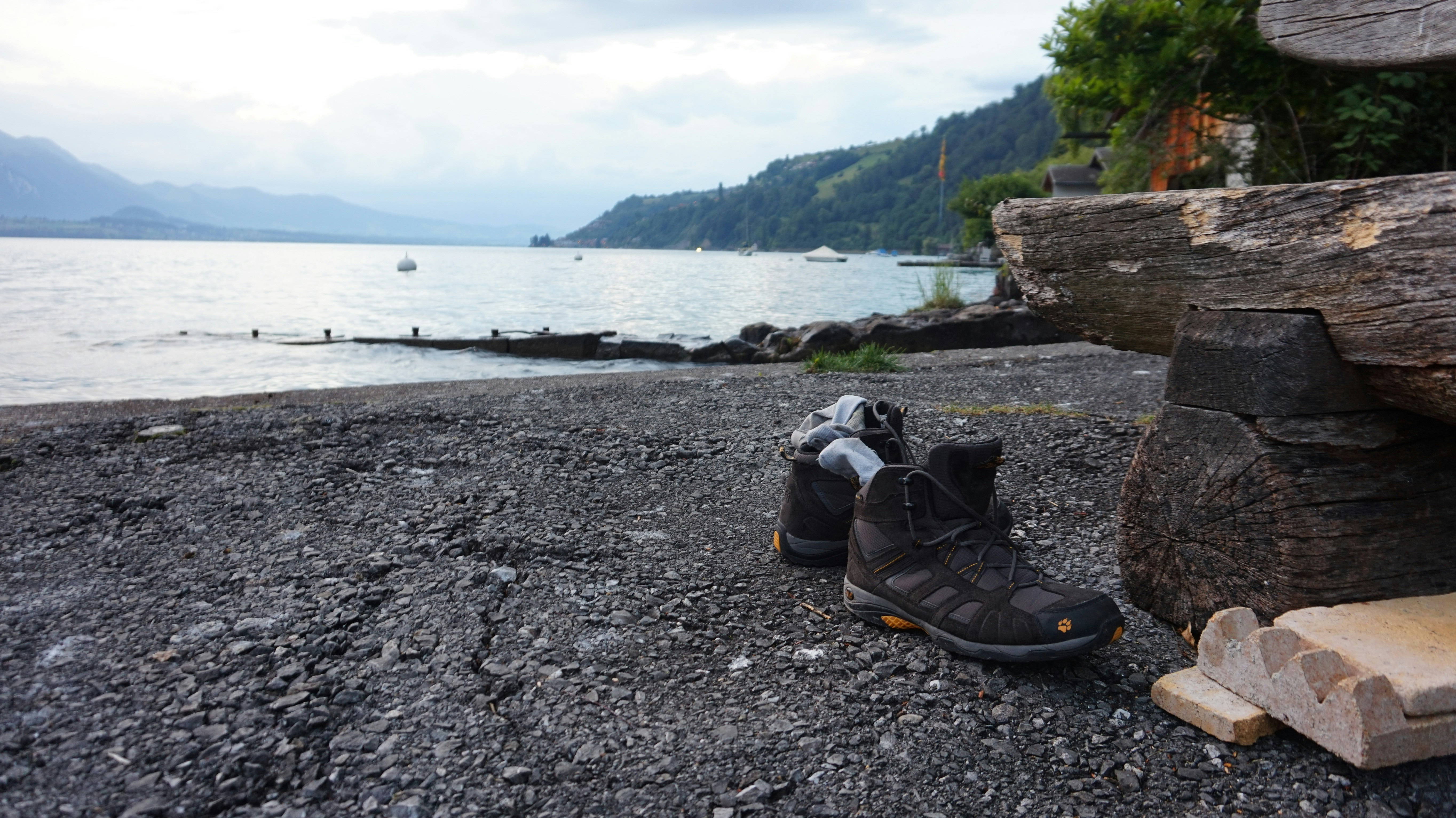 A pair of hiking boots sitting on the shore of a lake photo – Free ...