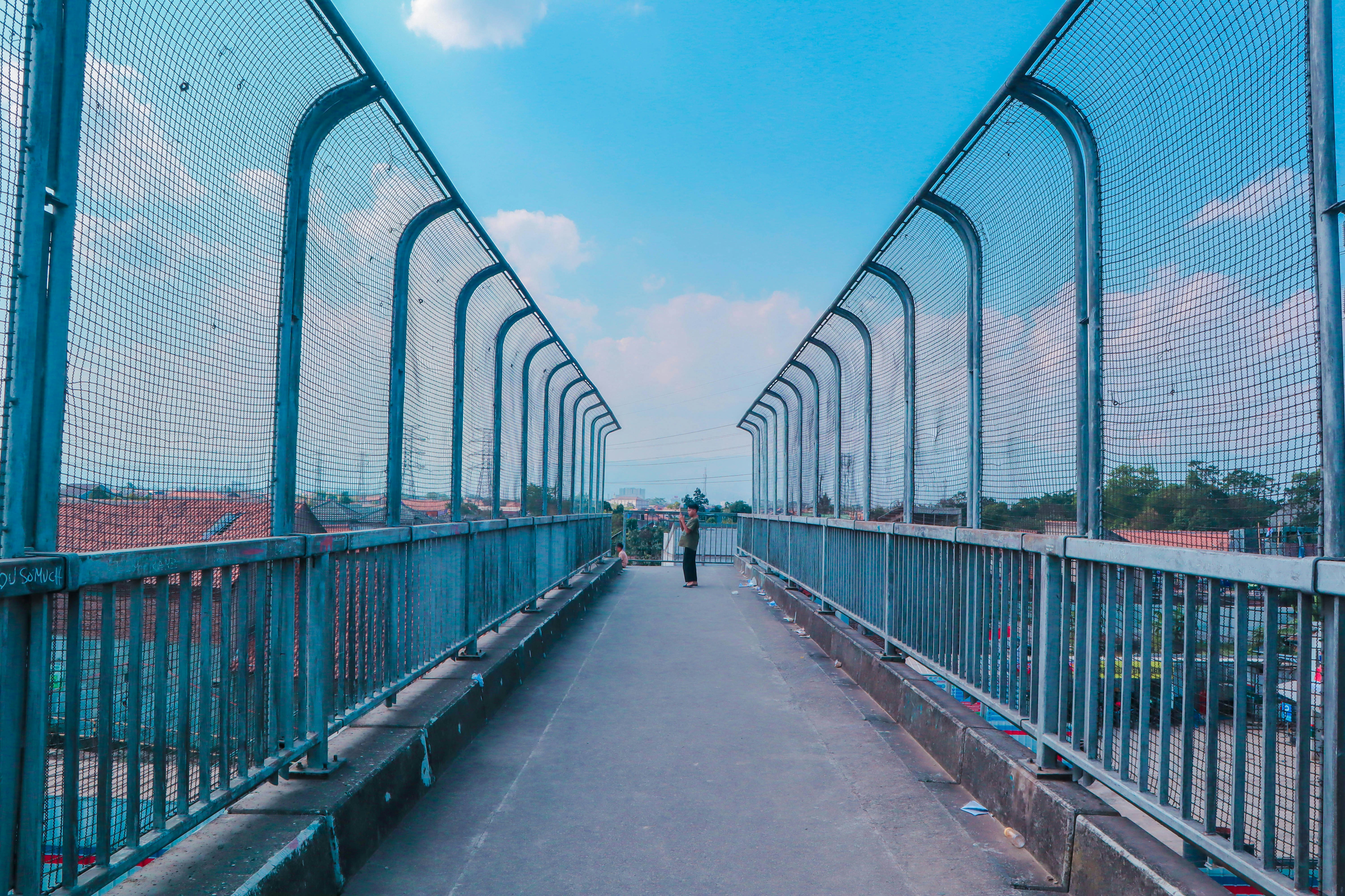 A person walking across a bridge with a sky background photo – Free ...