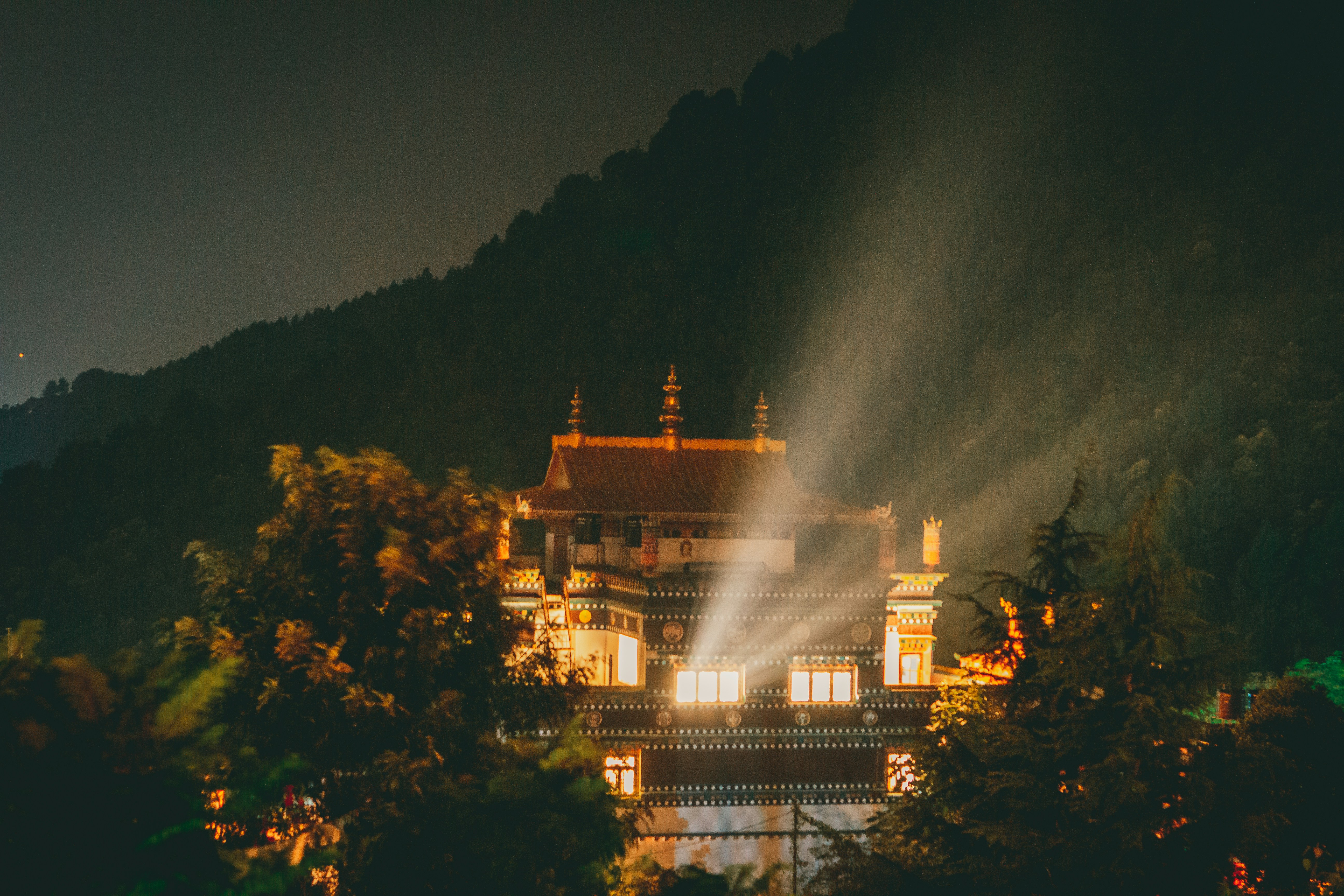 Beacons in the Mist: Night-Illuminated Temple Above the Forest Ridge