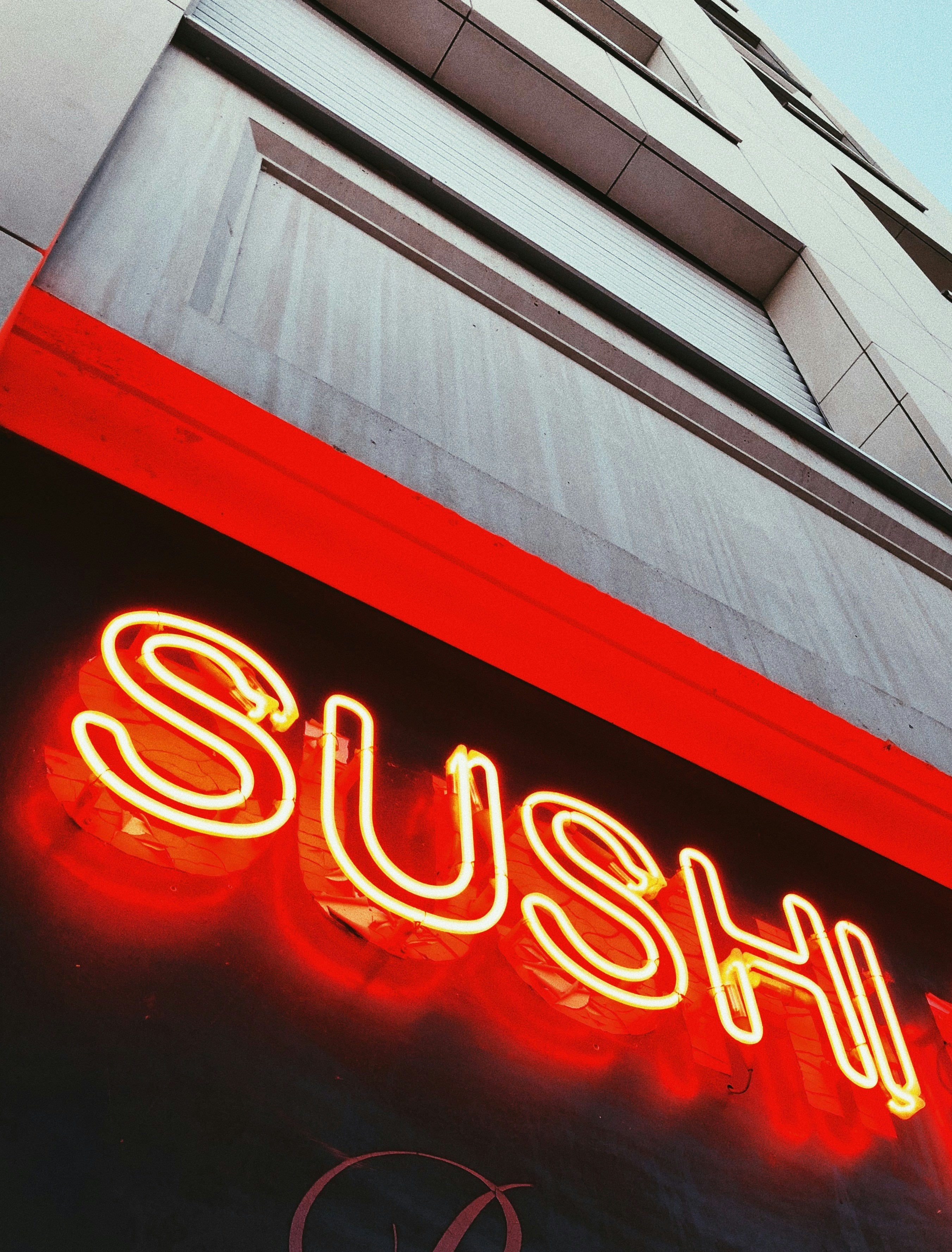 Tilted City Facade Bathed in Neon Sushi Sign