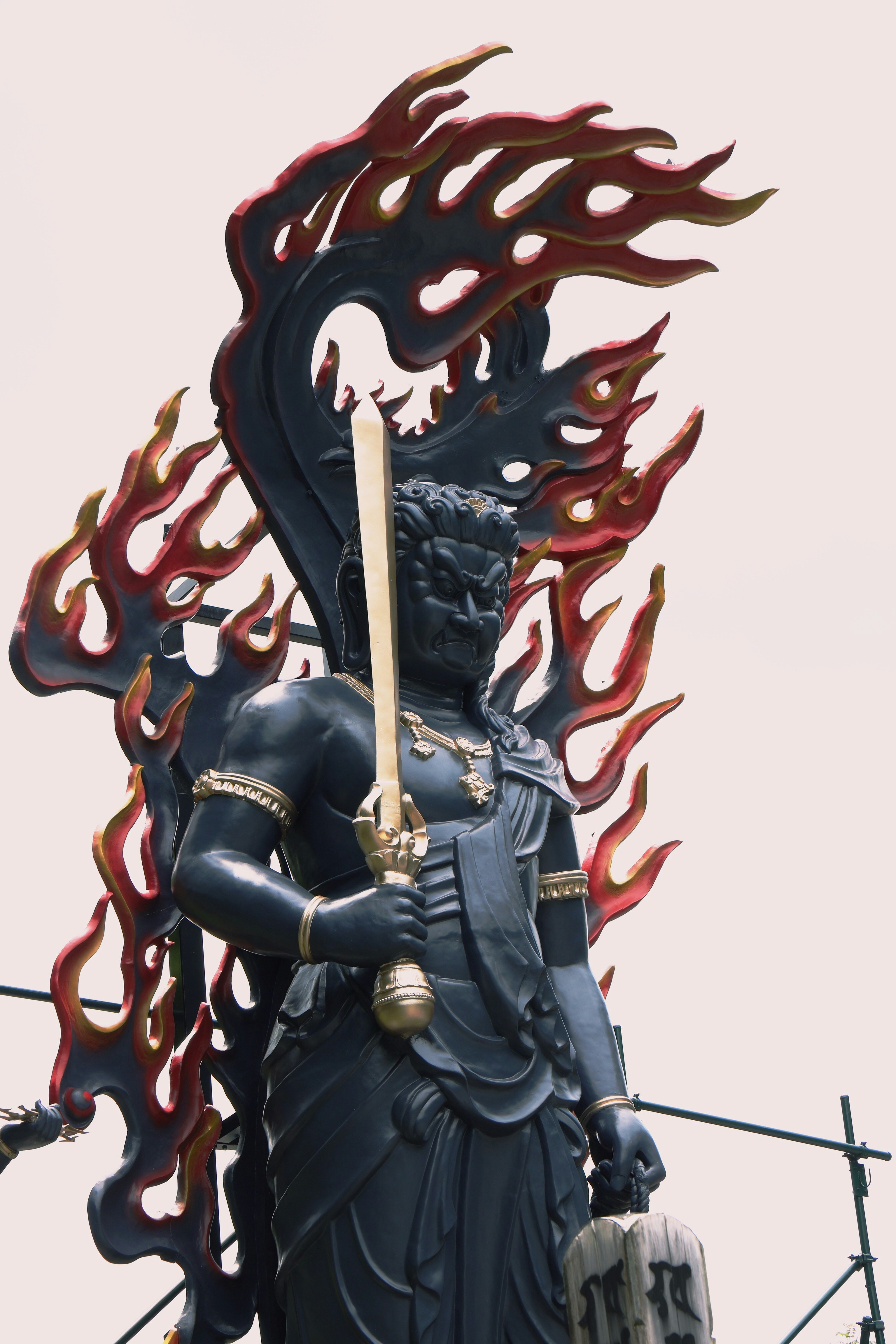 Majestic black statue with fiery red and gold accents, wielding a sword and shield, representing a powerful guardian figure.